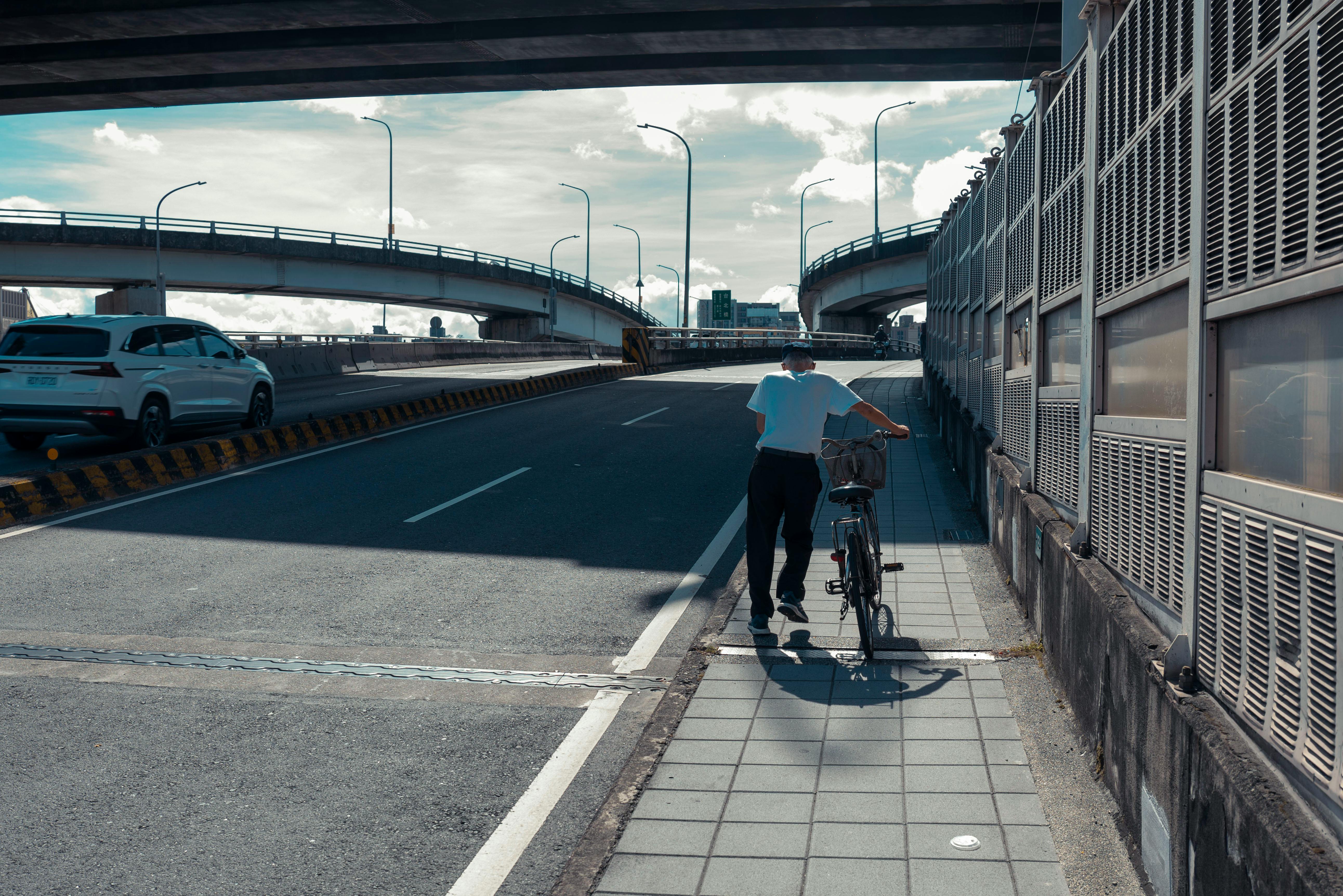 A person riding a bike on a road under an overpass · Free Stock Photo