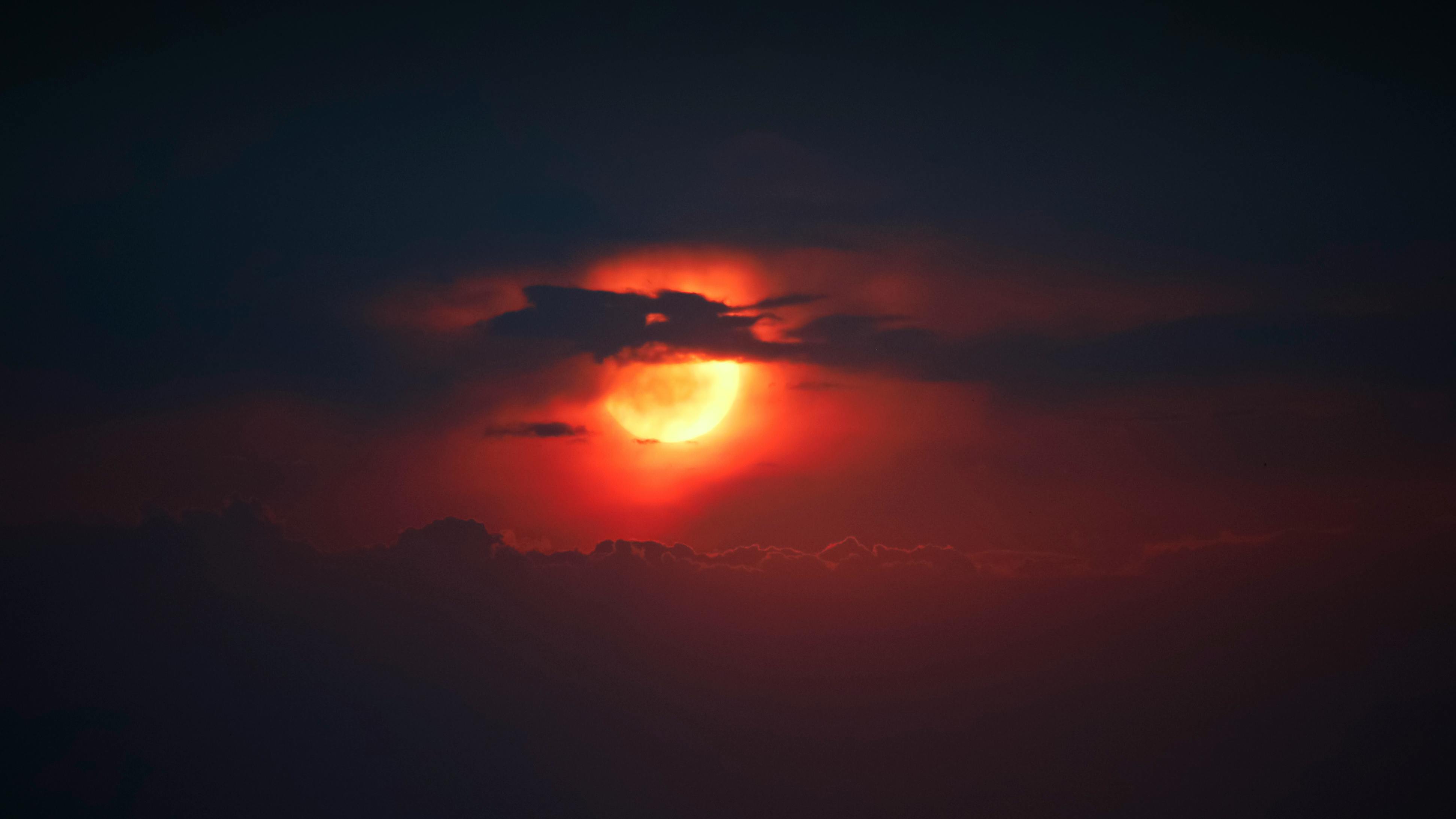 The sun is setting over the clouds in a dark sky · Free Stock Photo