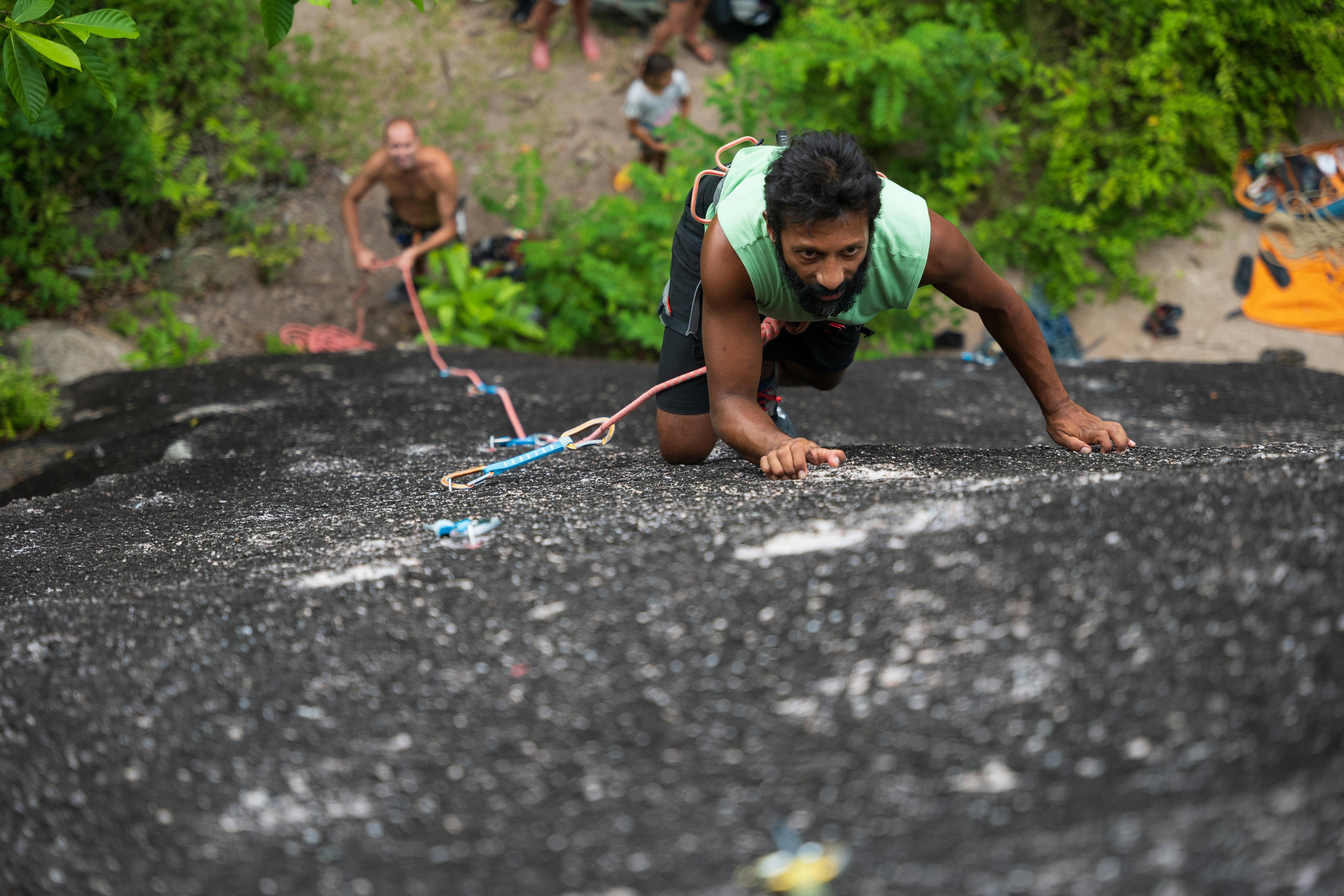 A man climbing up a rock face with a rope · Free Stock Photo