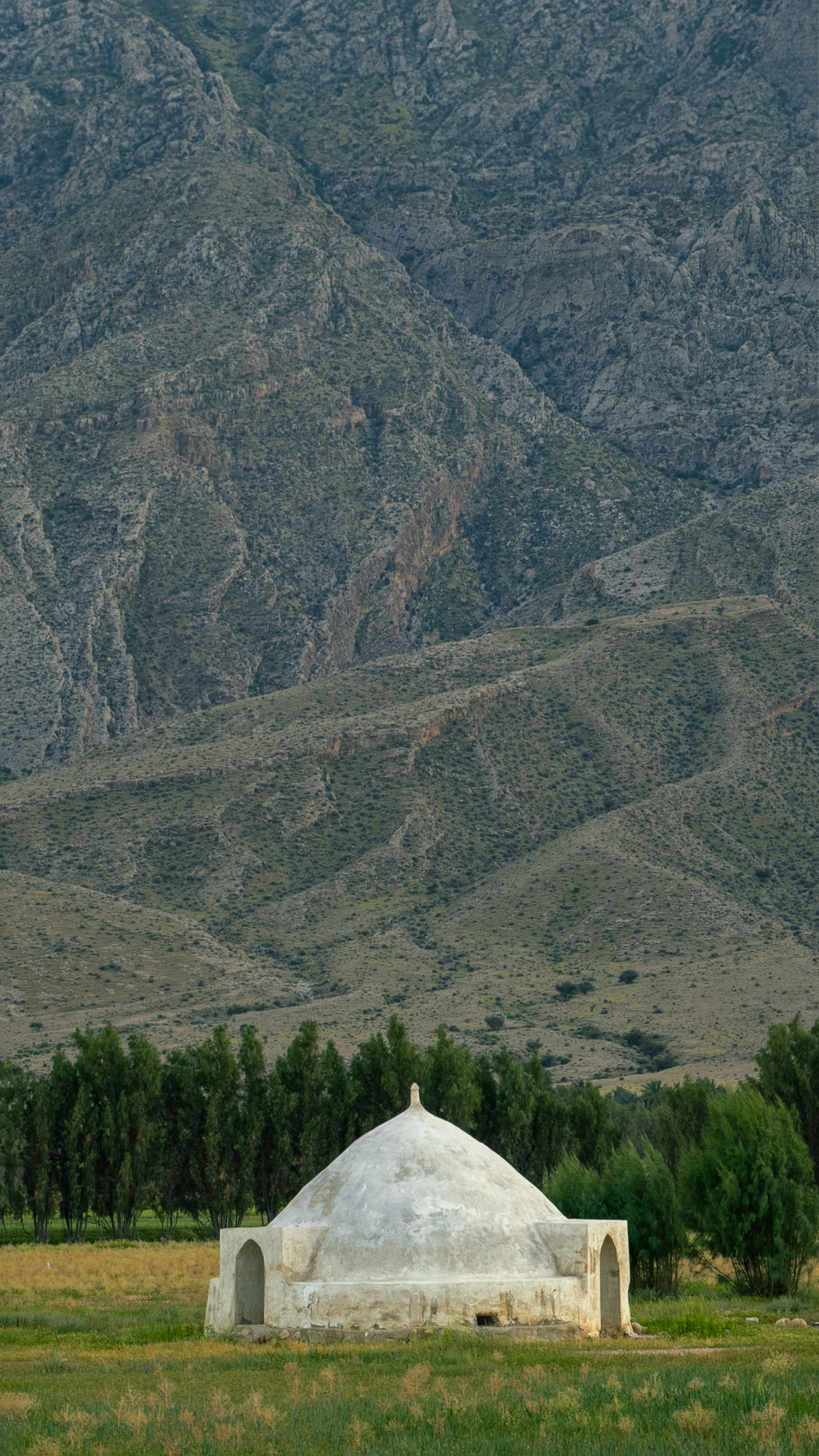 Ancient Building on Grassland with Mountain behind · Free Stock Photo