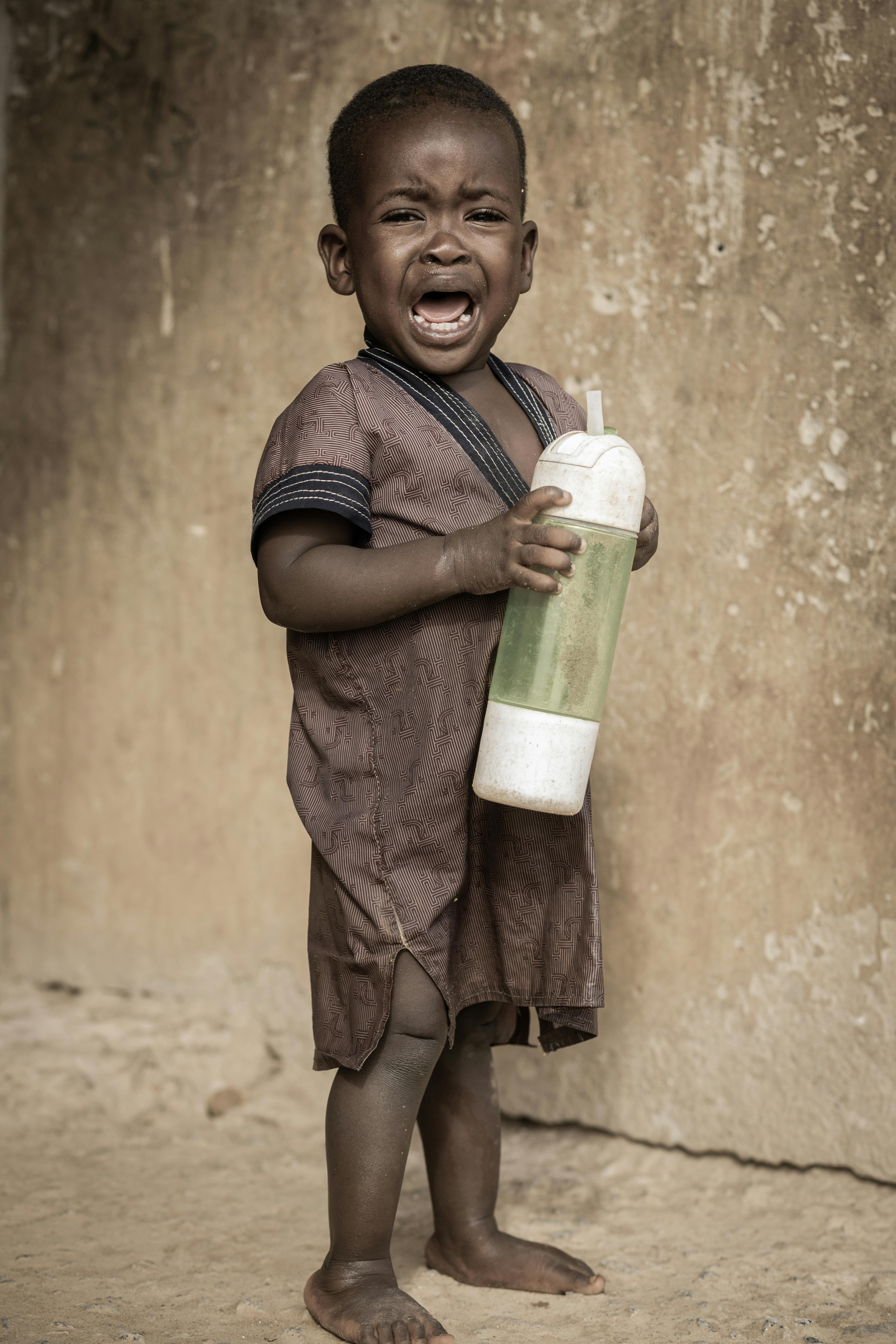 Crying Little Boy Holding a Empty Water Bottle · Free Stock Photo
