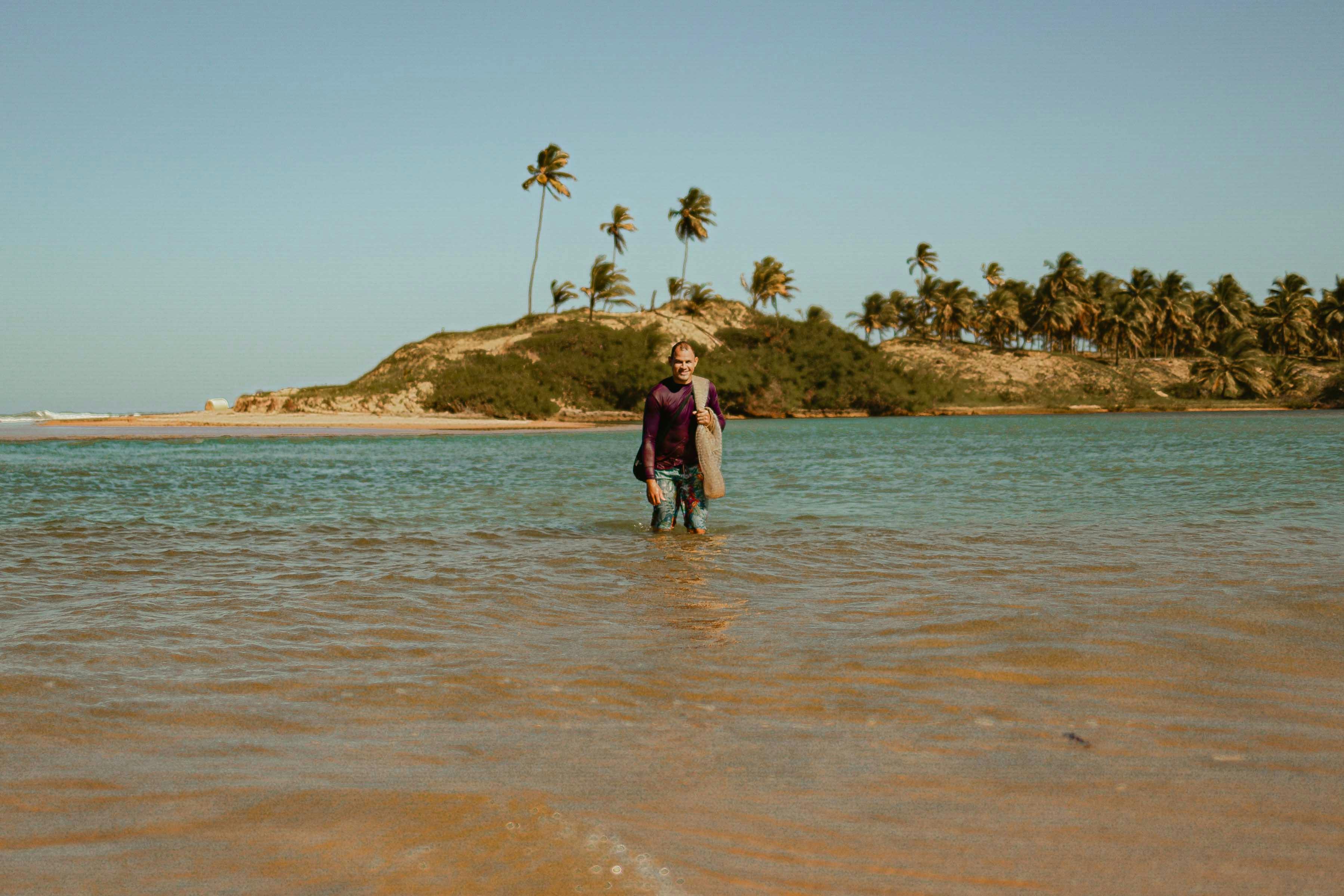 A Man Standing Knee Deep in the Water on the Background of an Island ...