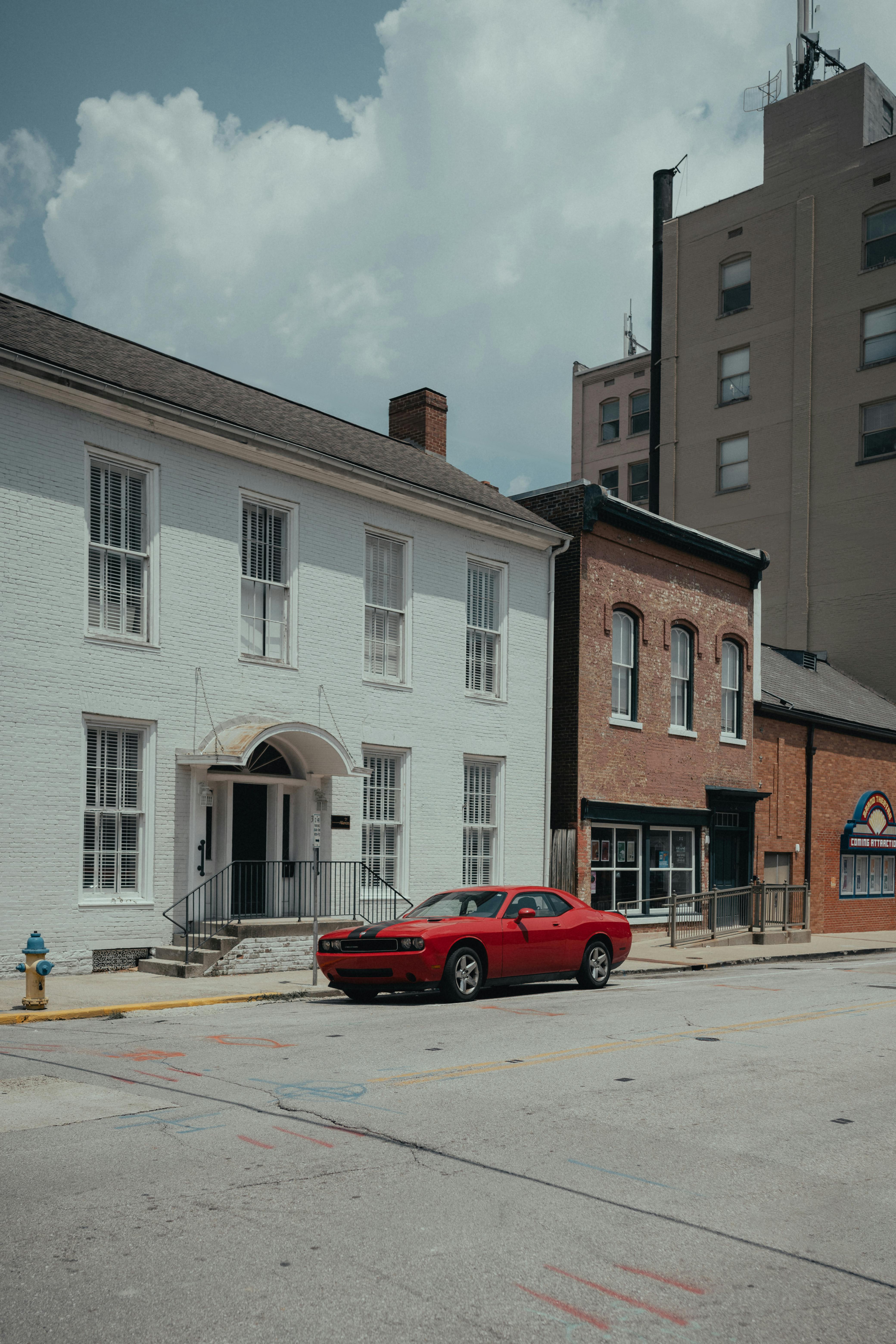 A red car parked in front of a white building · Free Stock Photo