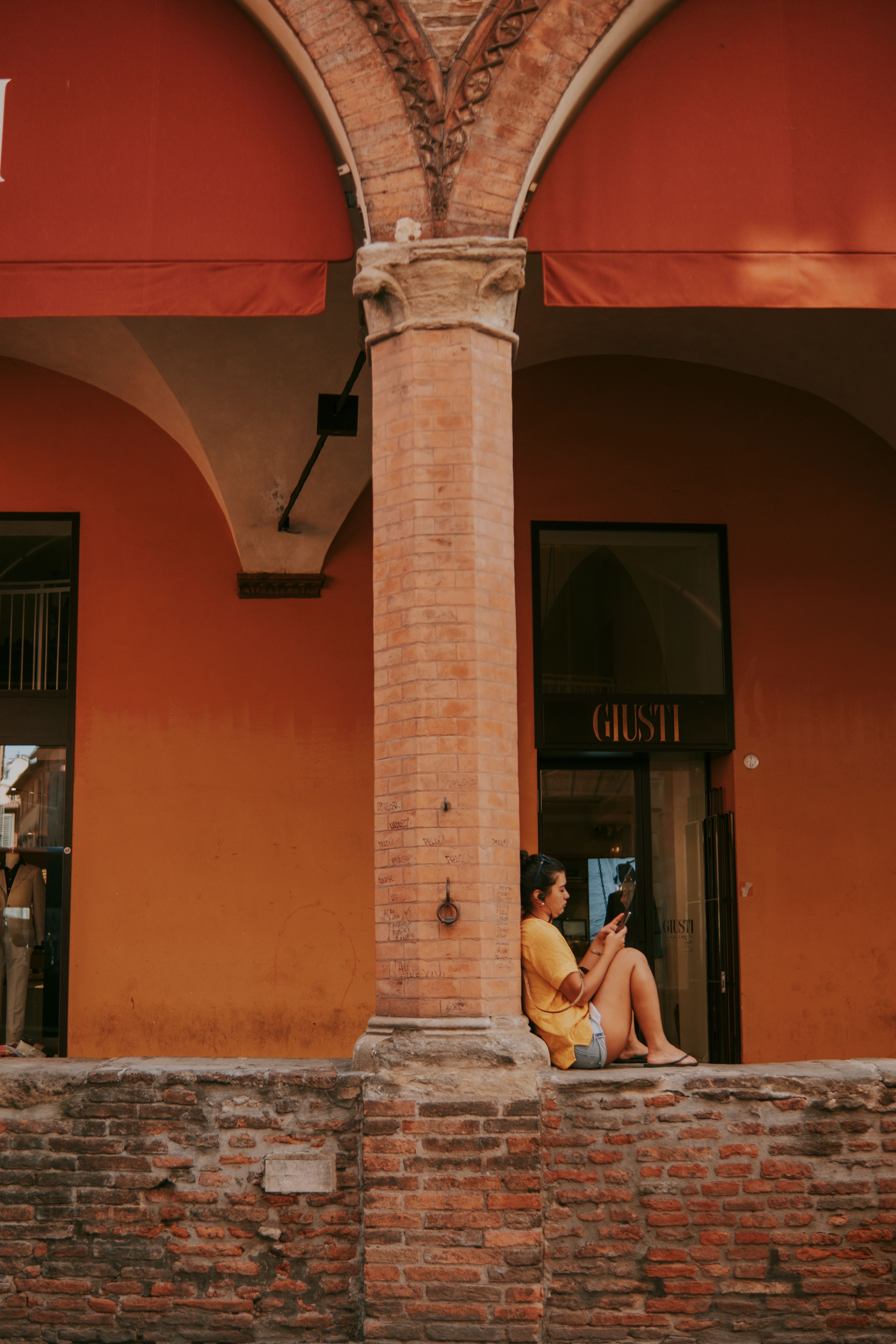 Woman Sitting by Column on Wall · Free Stock Photo