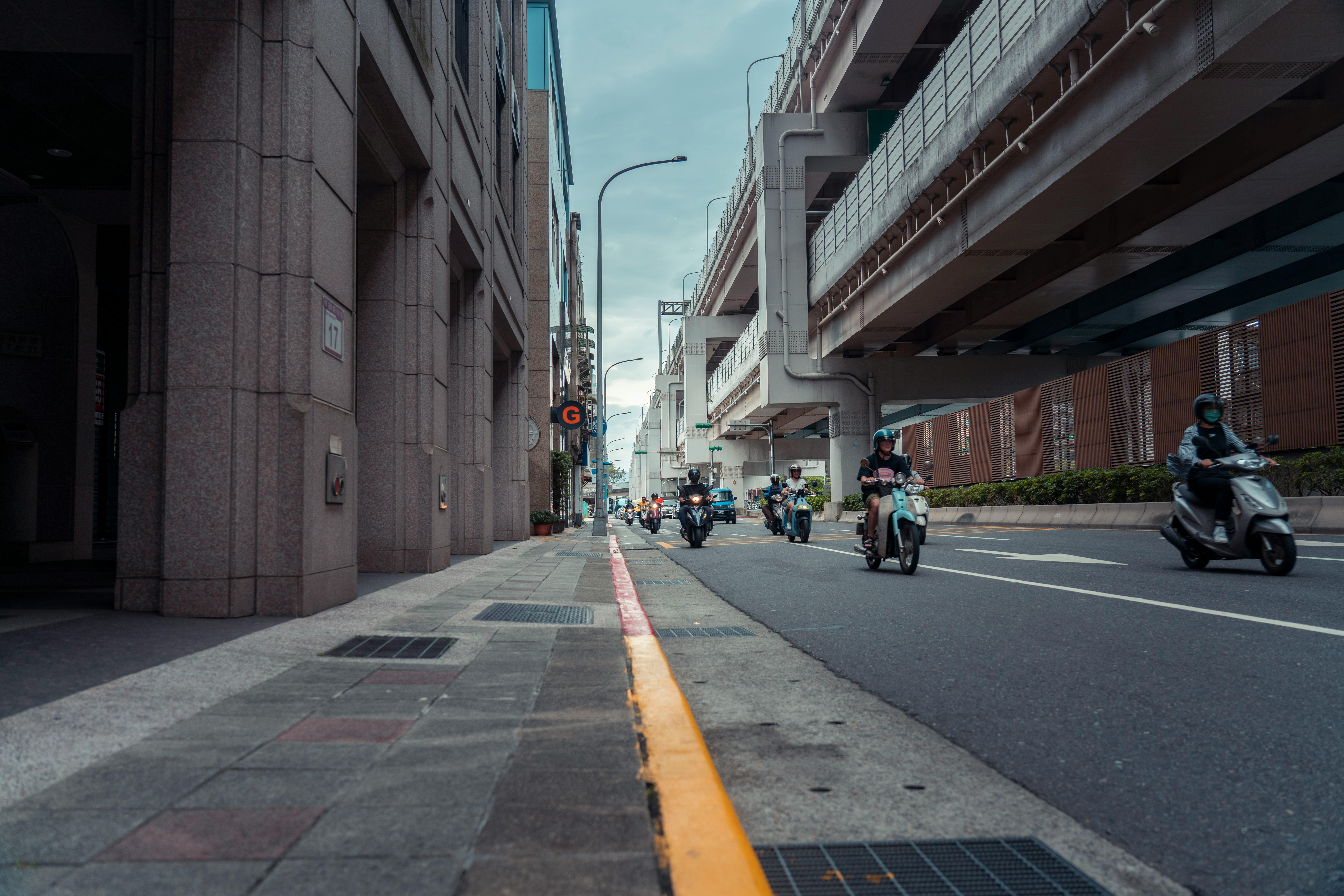View of Motor Scooters Riding on a Street between Buildings in a City ...