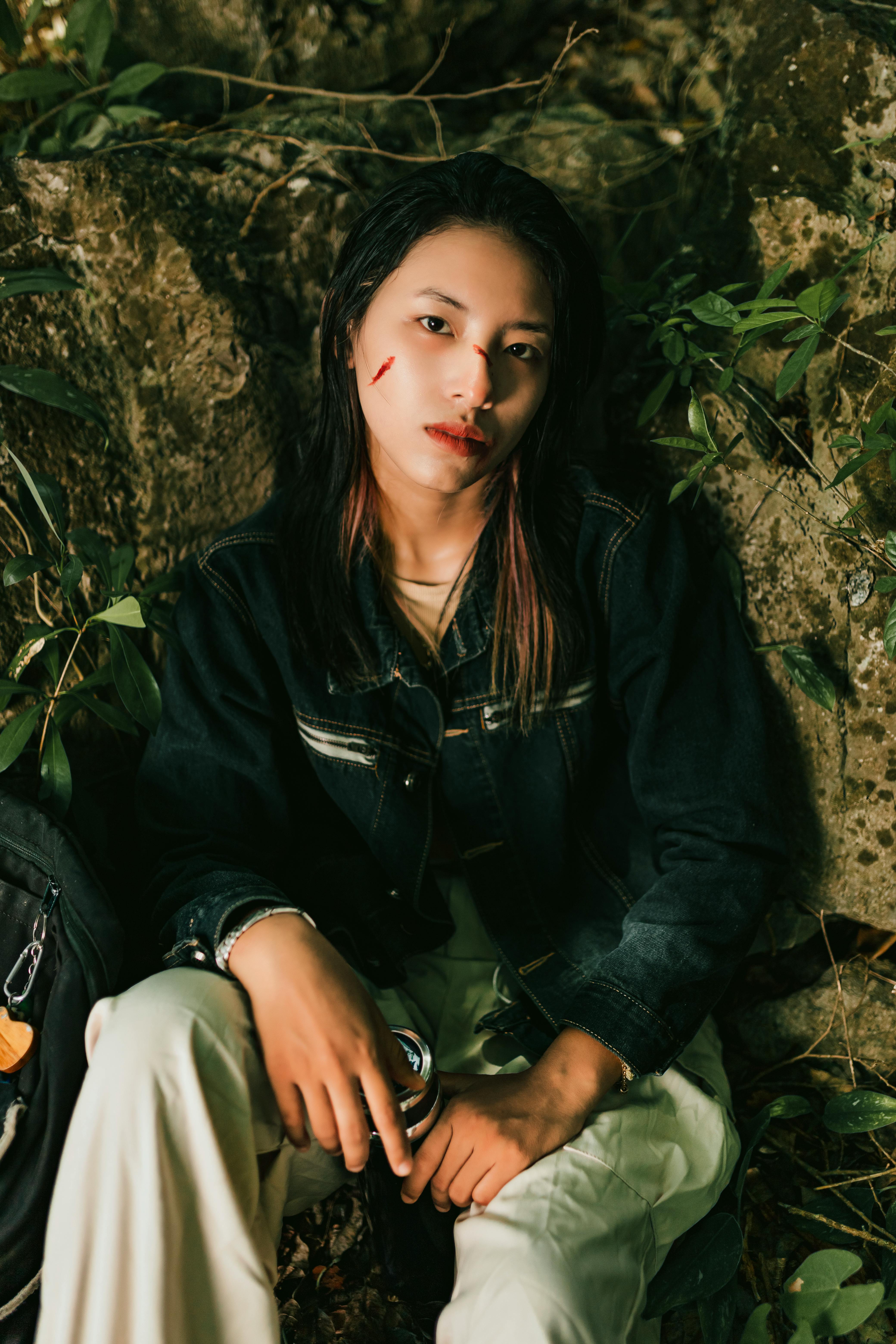 Beautiful Woman with Wounds on Face Sitting by Rock · Free Stock Photo