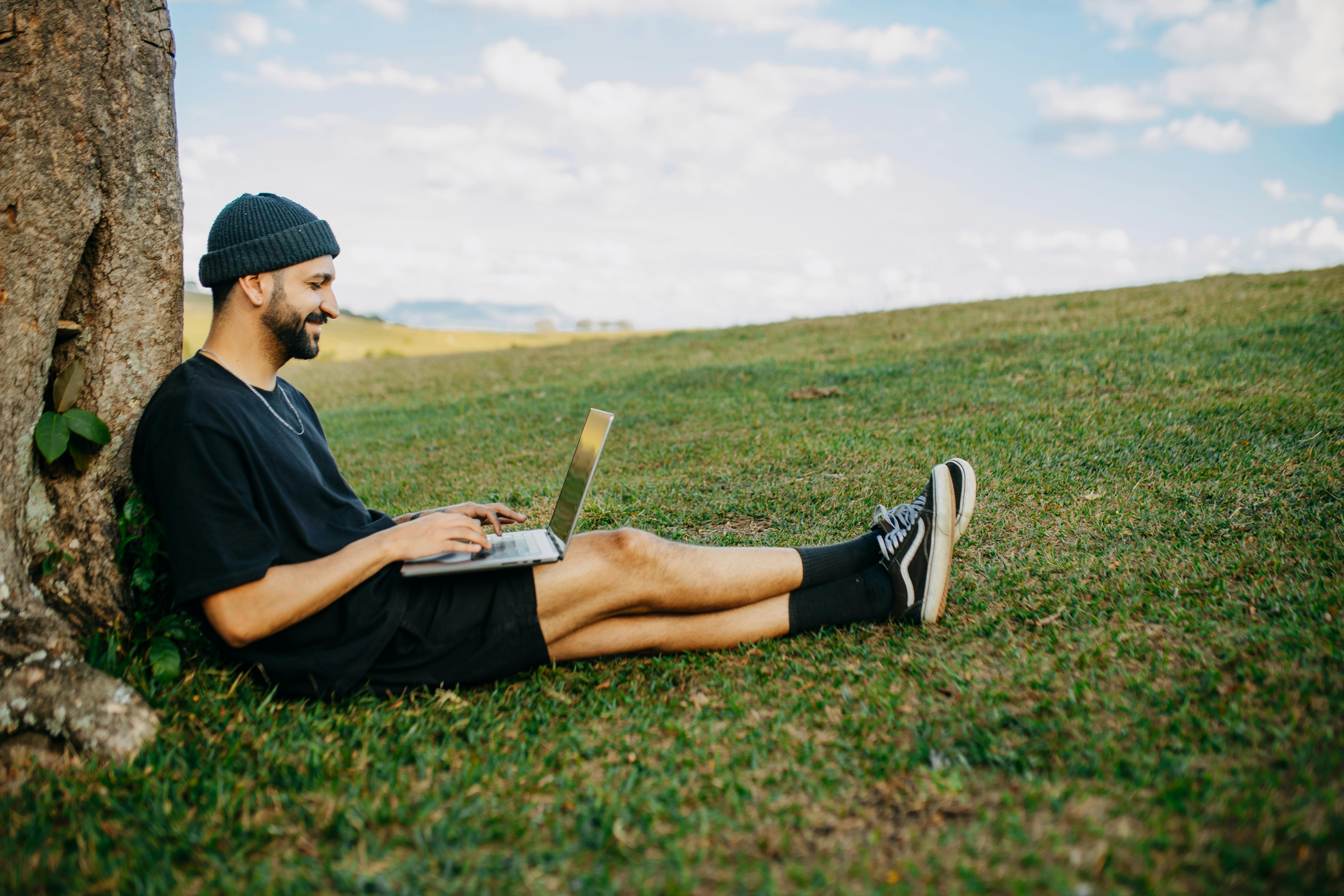 Man Sitting by Tree and Working on Laptop · Free Stock Photo