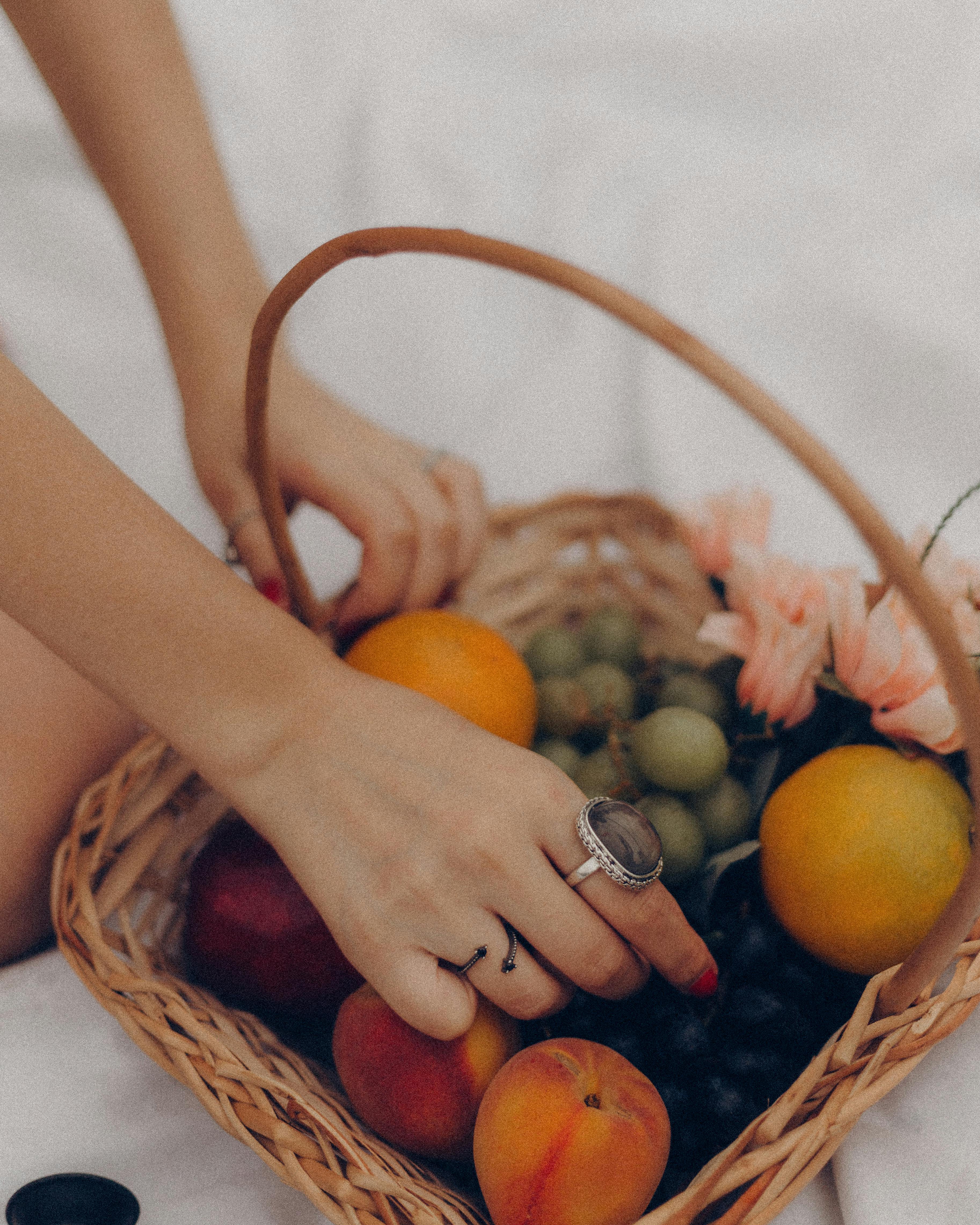 Hand Picking Fruit Out of Wicker Basket · Free Stock Photo