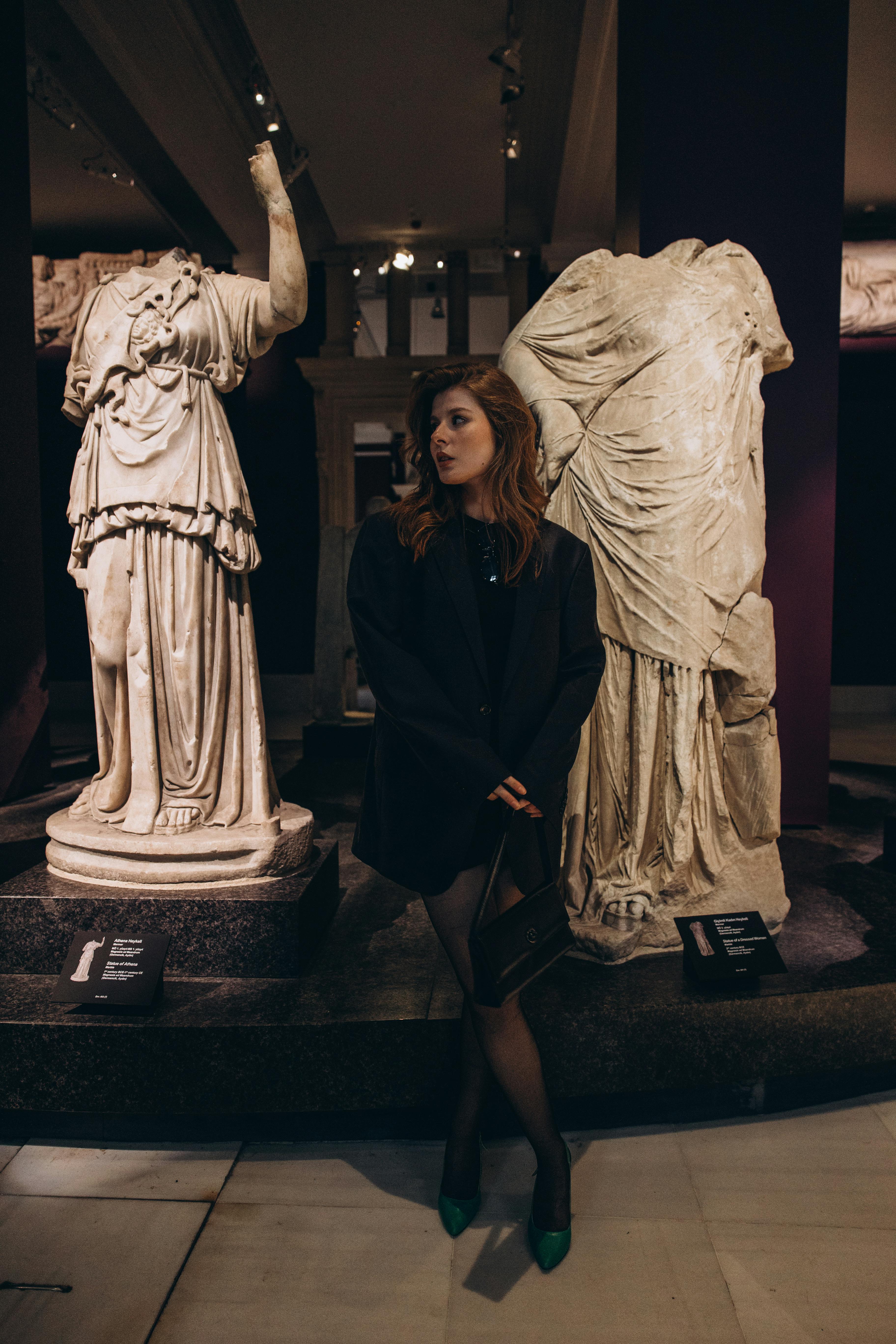 Woman Sitting in a Museum Behind a Dying Gaul Sculpture · Free Stock Photo