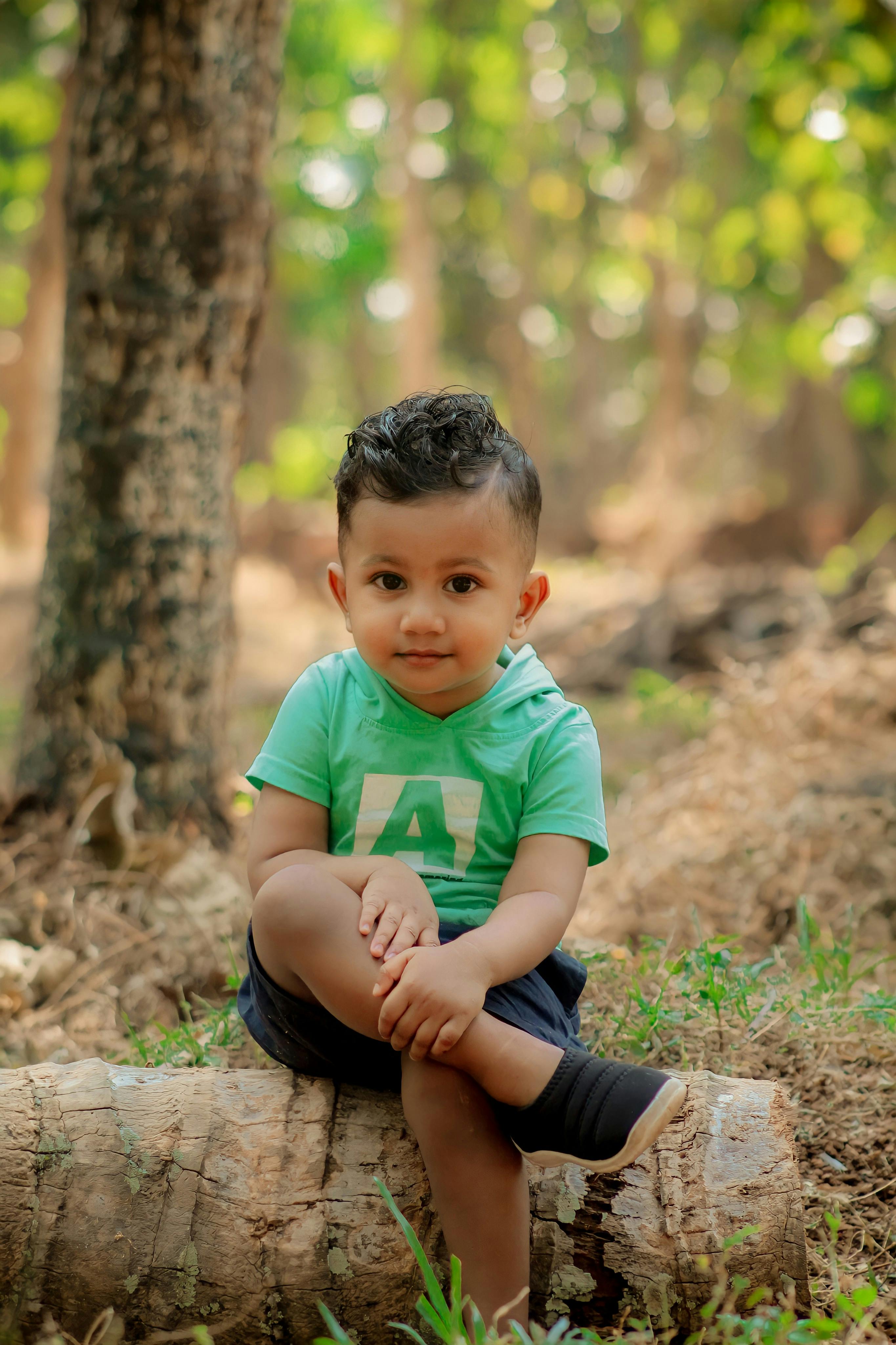 Niño Sentado En El Tronco De Un árbol · Foto de stock gratuita