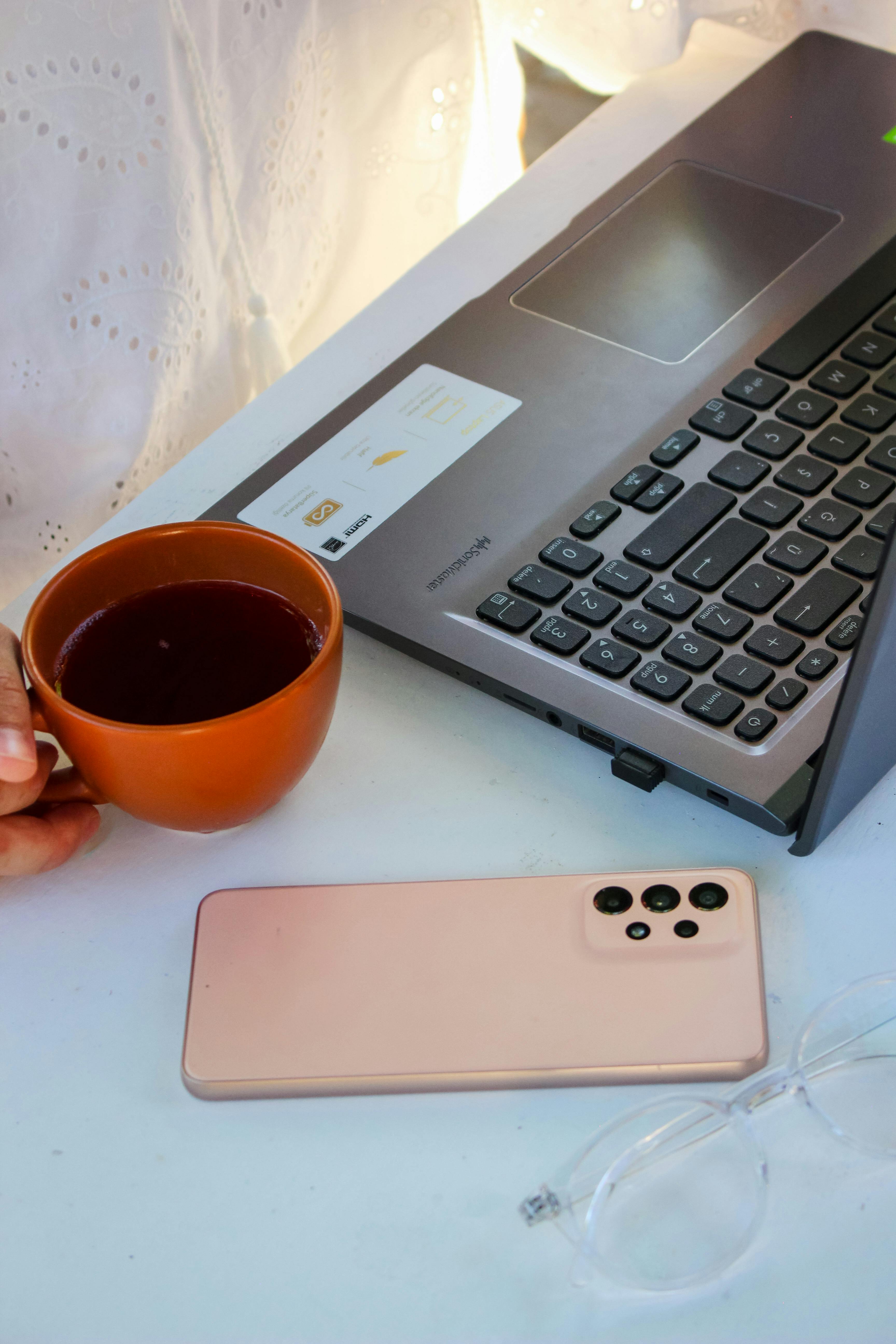 Samsung Phone on Desk Near Cup of Tea and Laptop · Free Stock Photo
