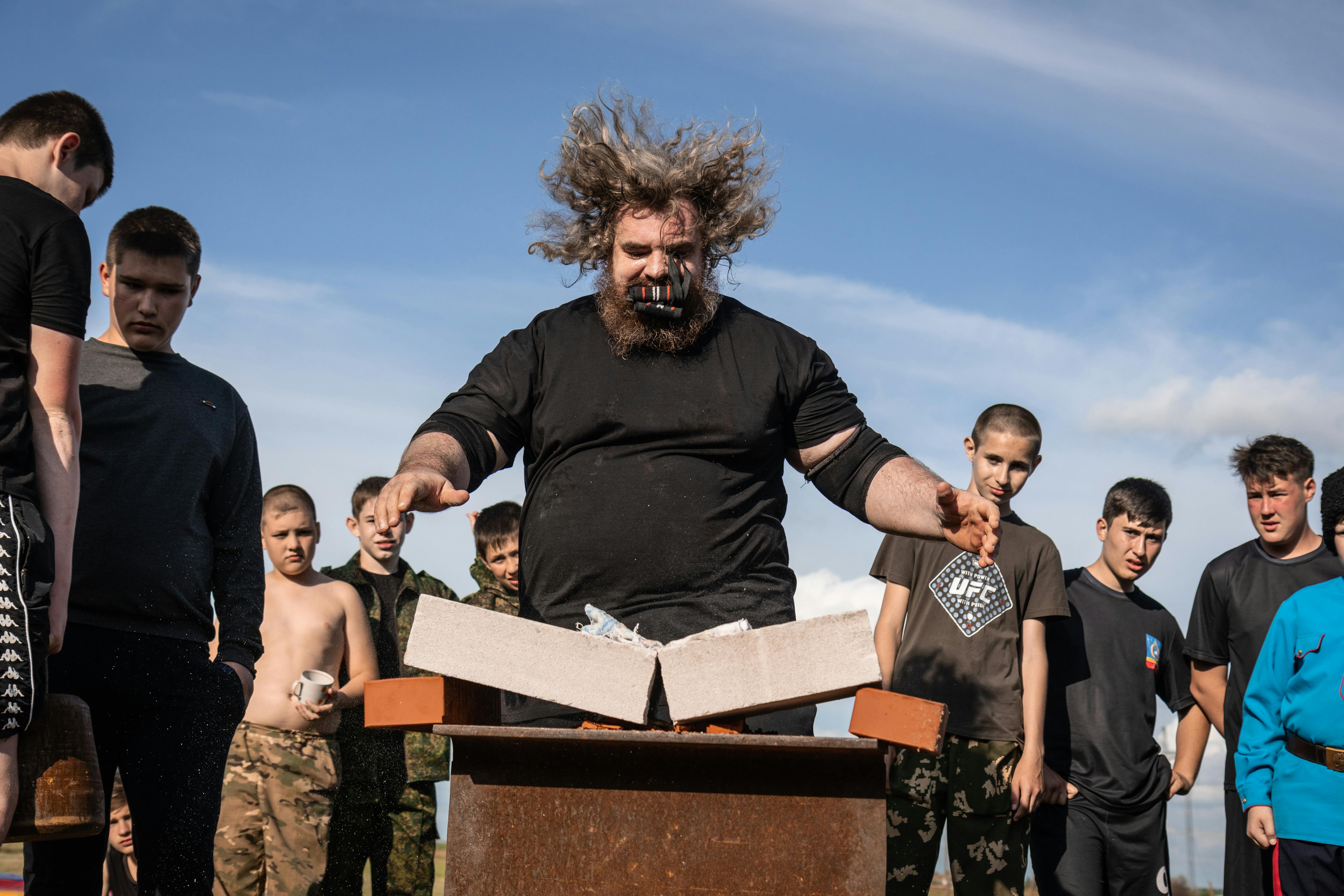 Strongman Standing in Front of Teenage Boys · Free Stock Photo