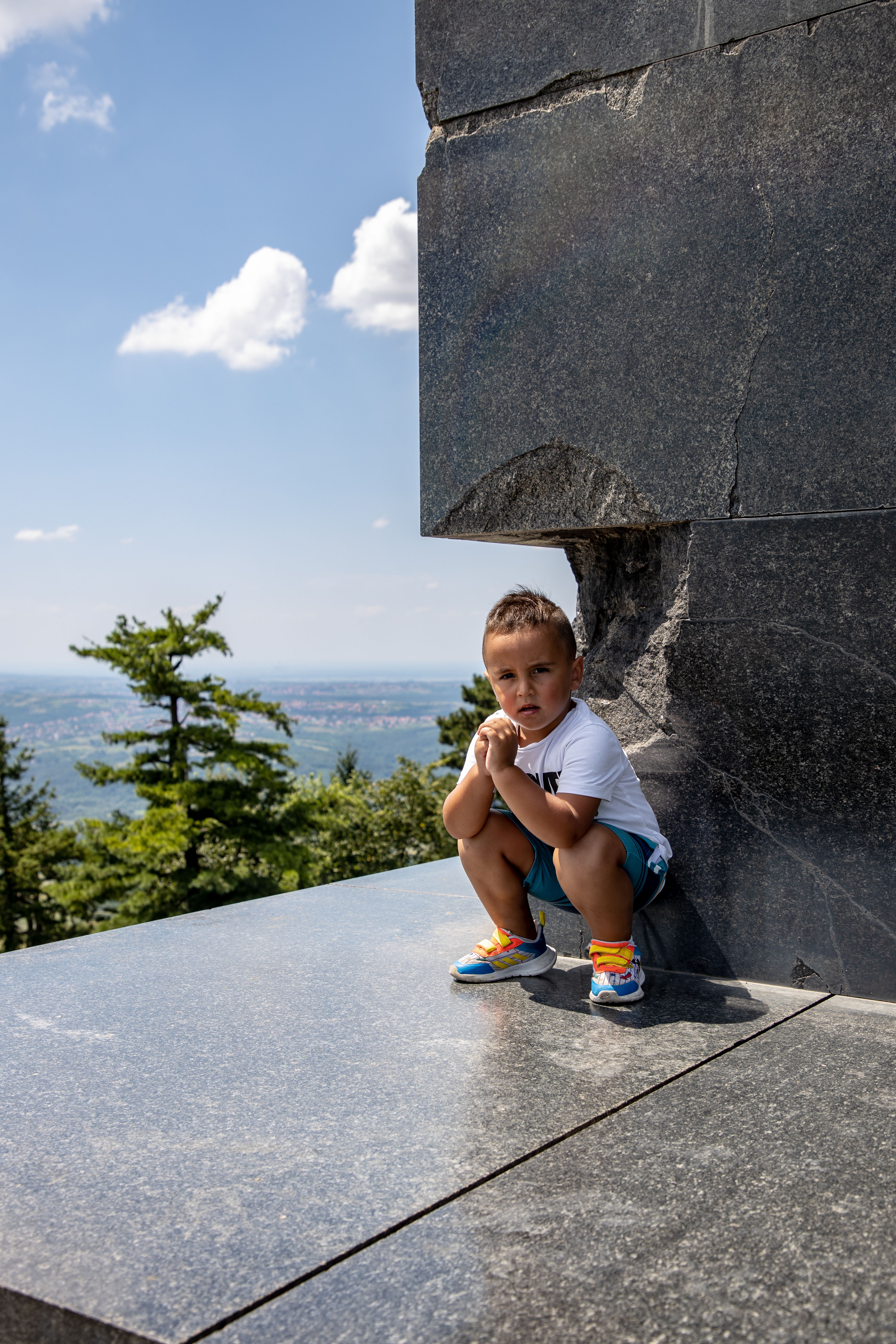 Photo of a Boy Crouching on a Granite Monument · Free Stock Photo