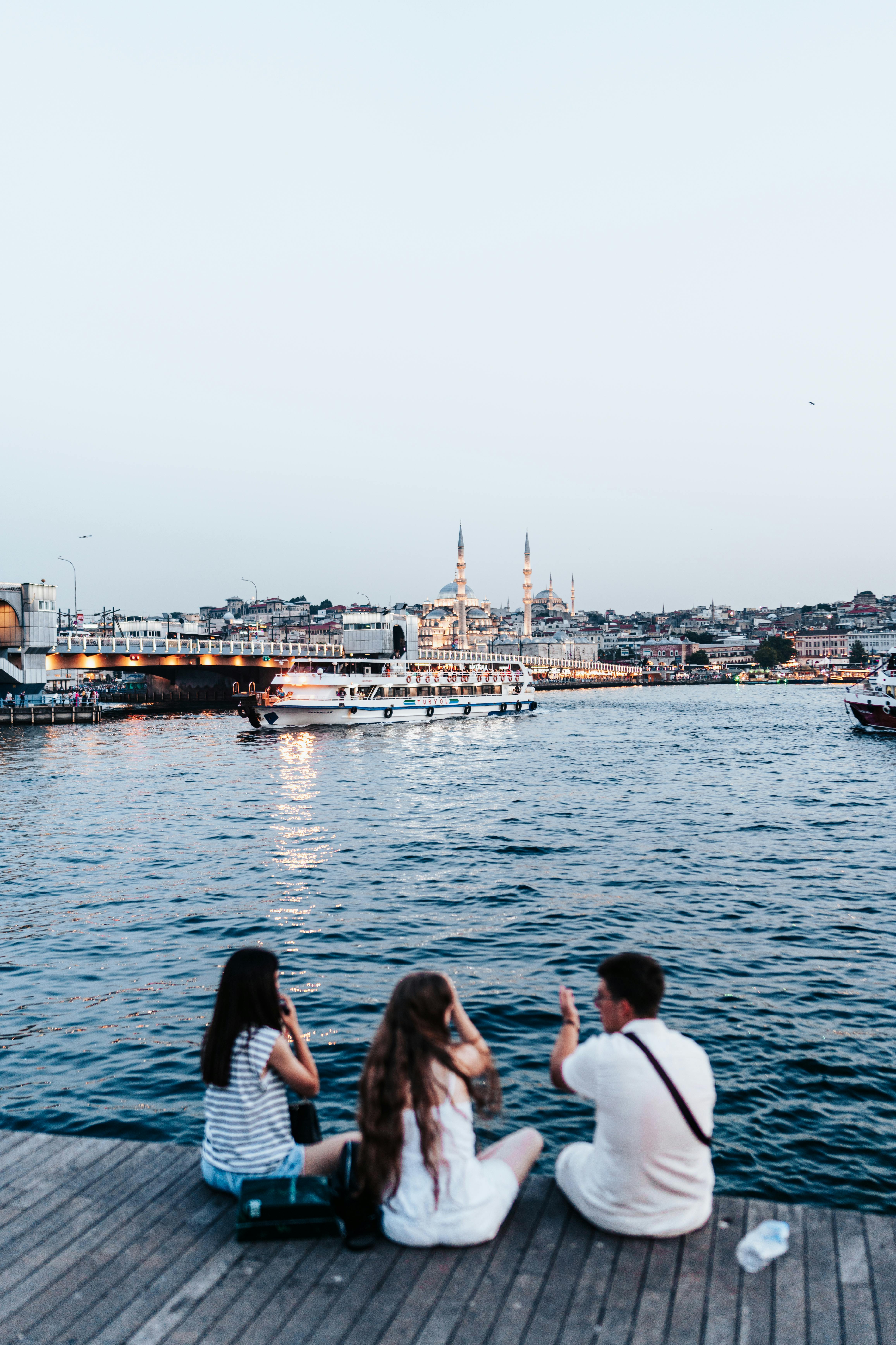 Group of Friends Sitting on a Jetty with a Ferry Sailing in the ...