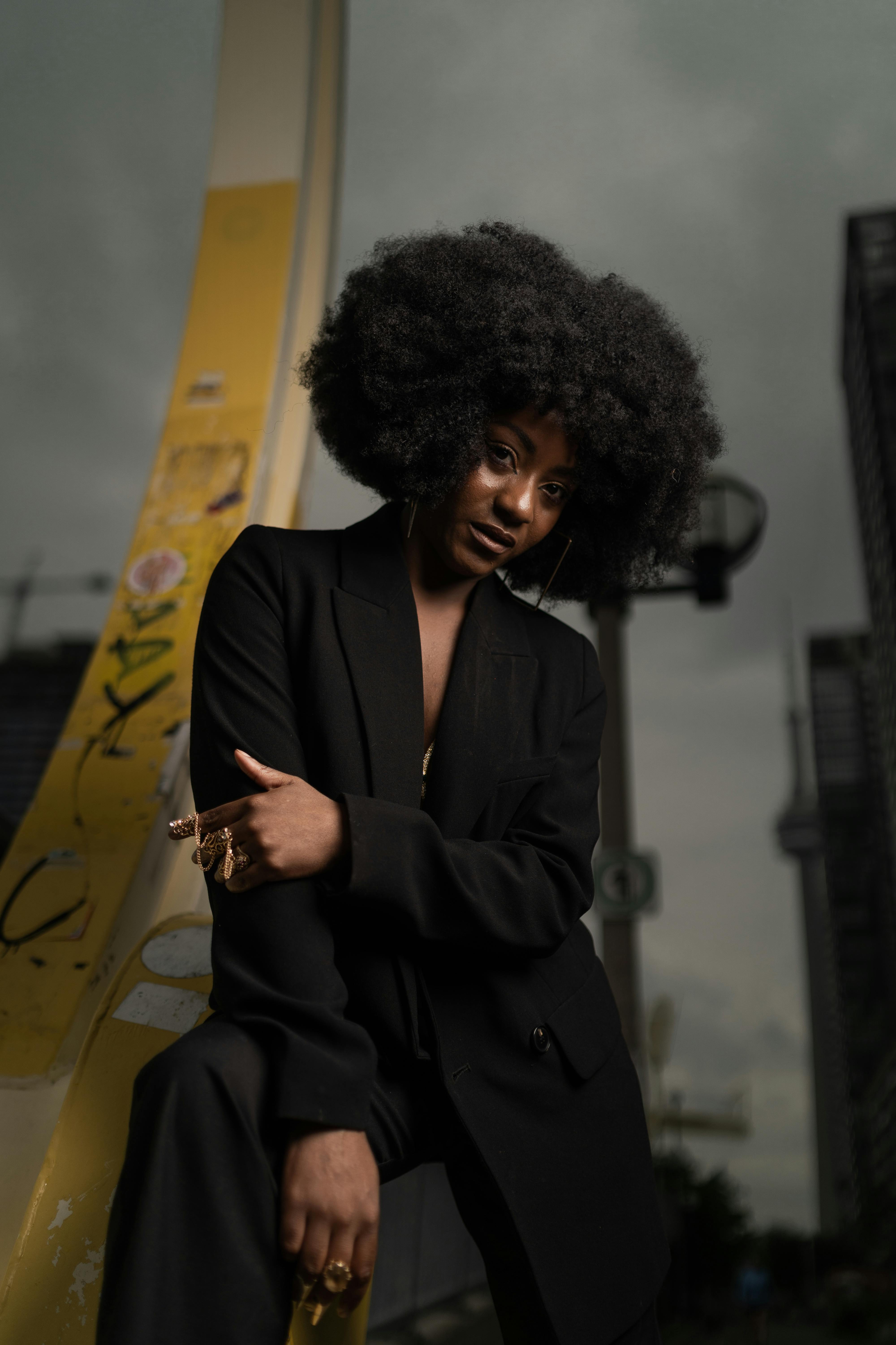 A woman with an afro wearing a suit and holding a pole · Free Stock Photo