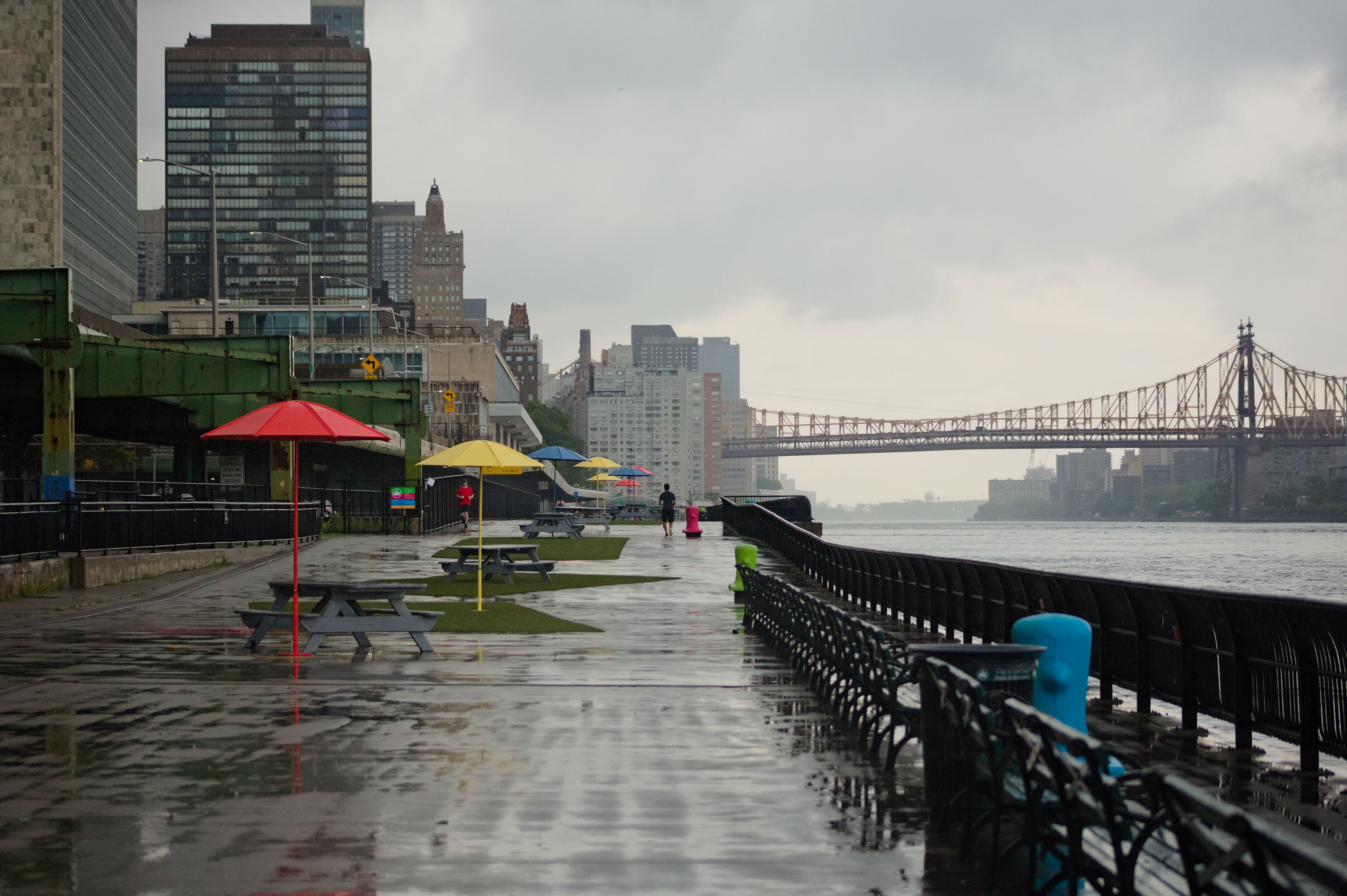 A Wet Sidewalk along the East River with View of the Queensboro Bridge ...