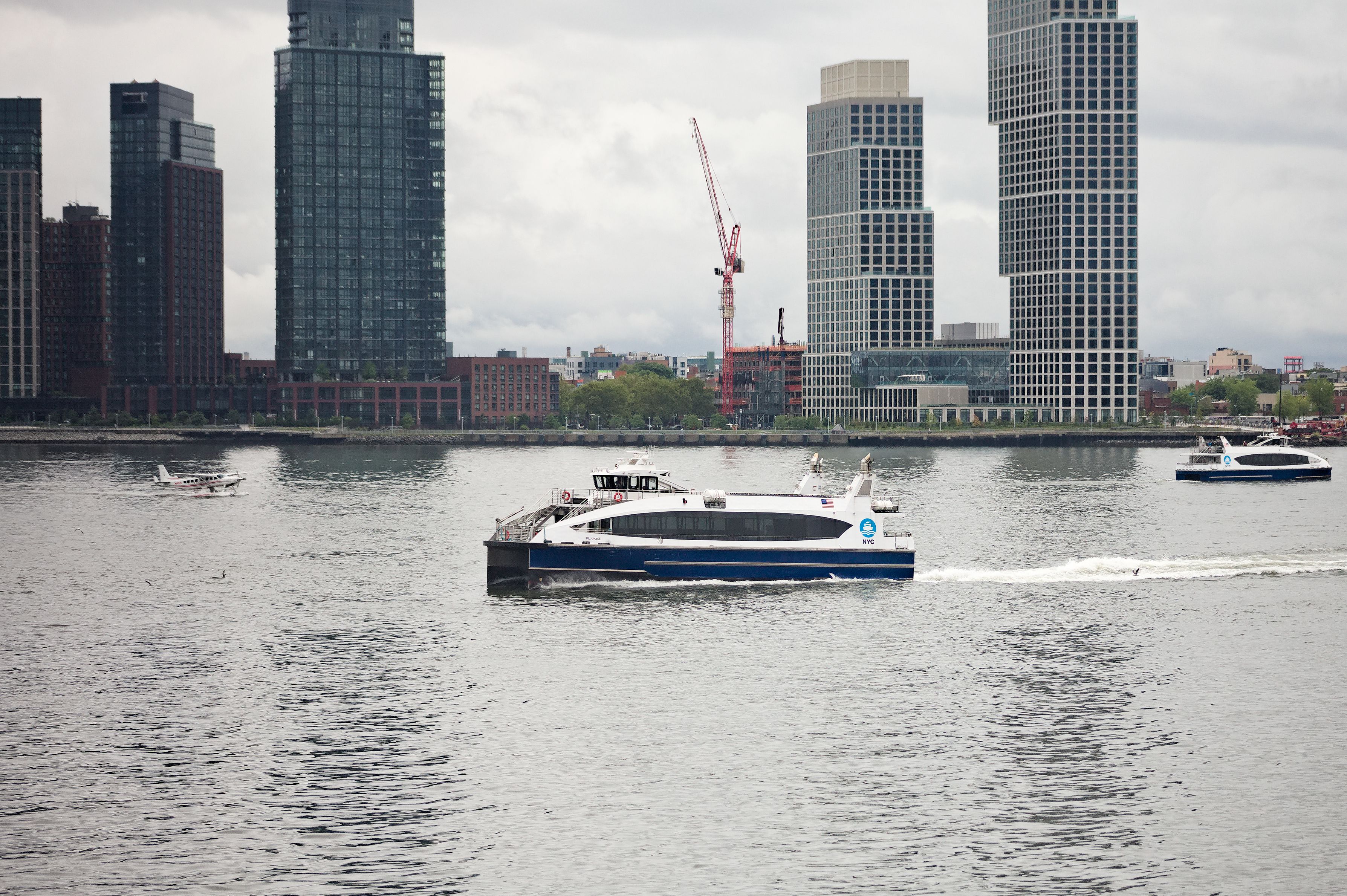 A ferry boat is traveling on the water near some tall buildings · Free ...