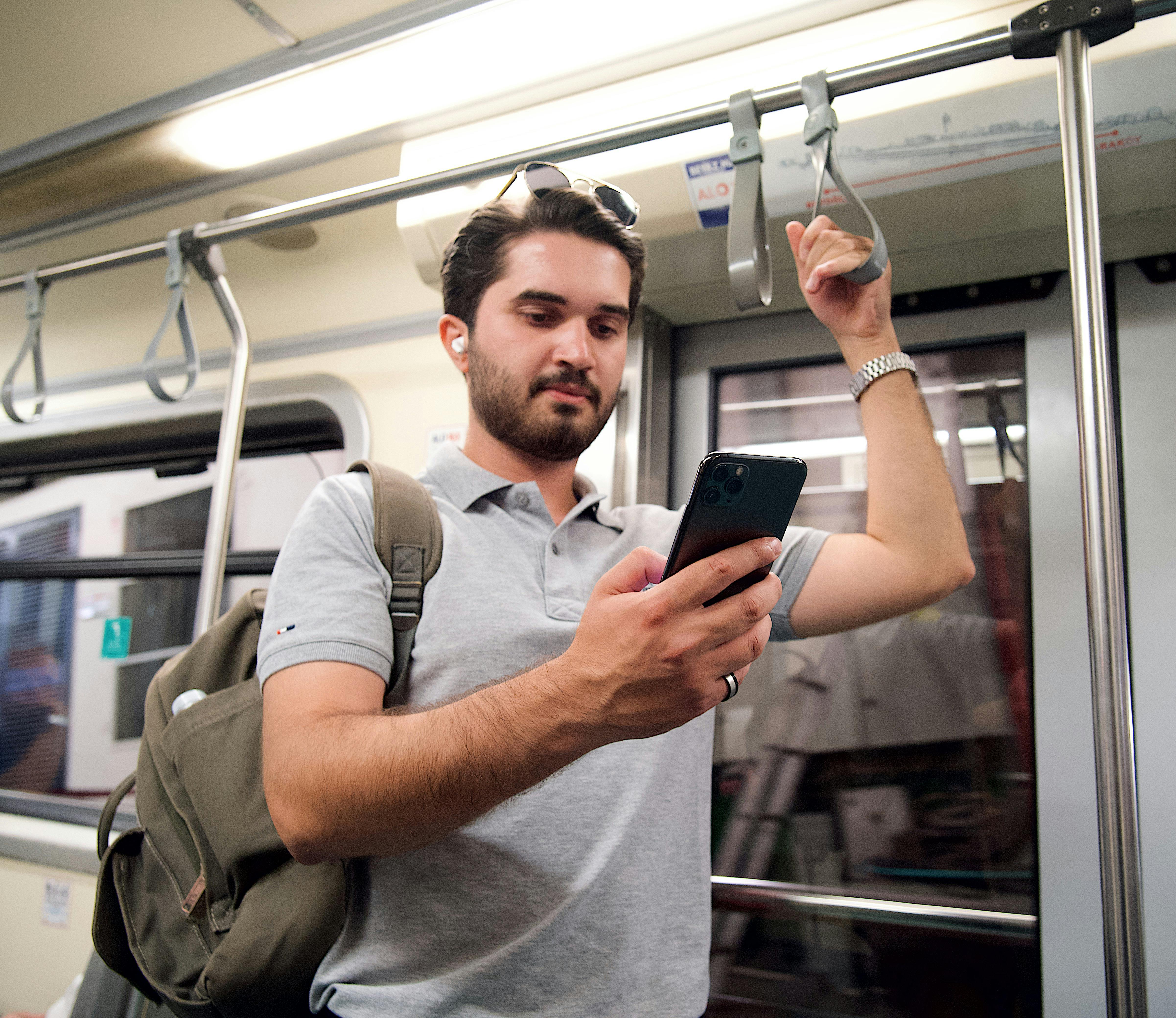 Man with Smartphone Standing in Public Transportation · Free Stock Photo
