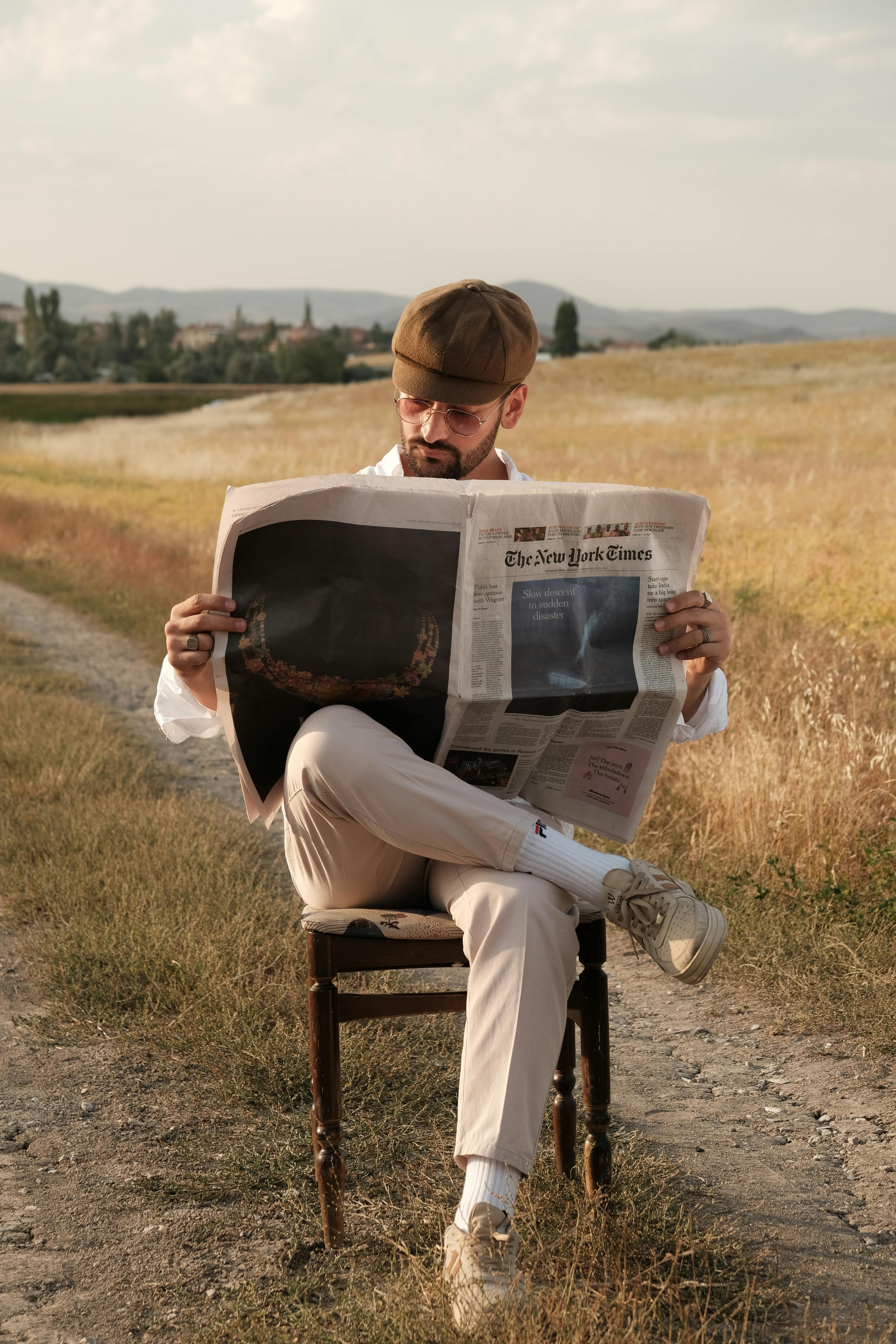 Elegant Man Sitting on a Chair on a Rural Field and Reading a Newspaper ...