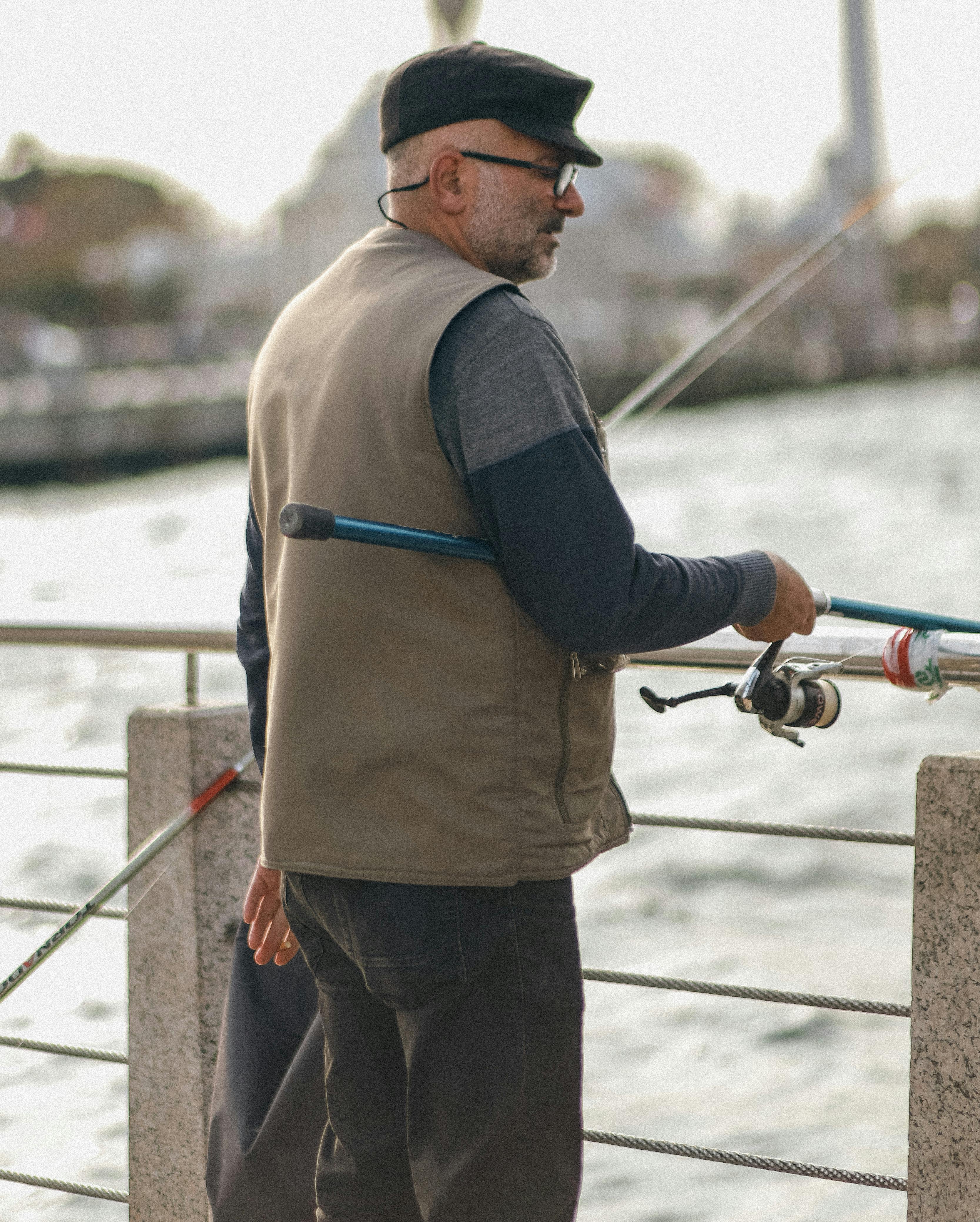 Angler with a Fishing Rod Supported on Bridge Railing · Free Stock Photo