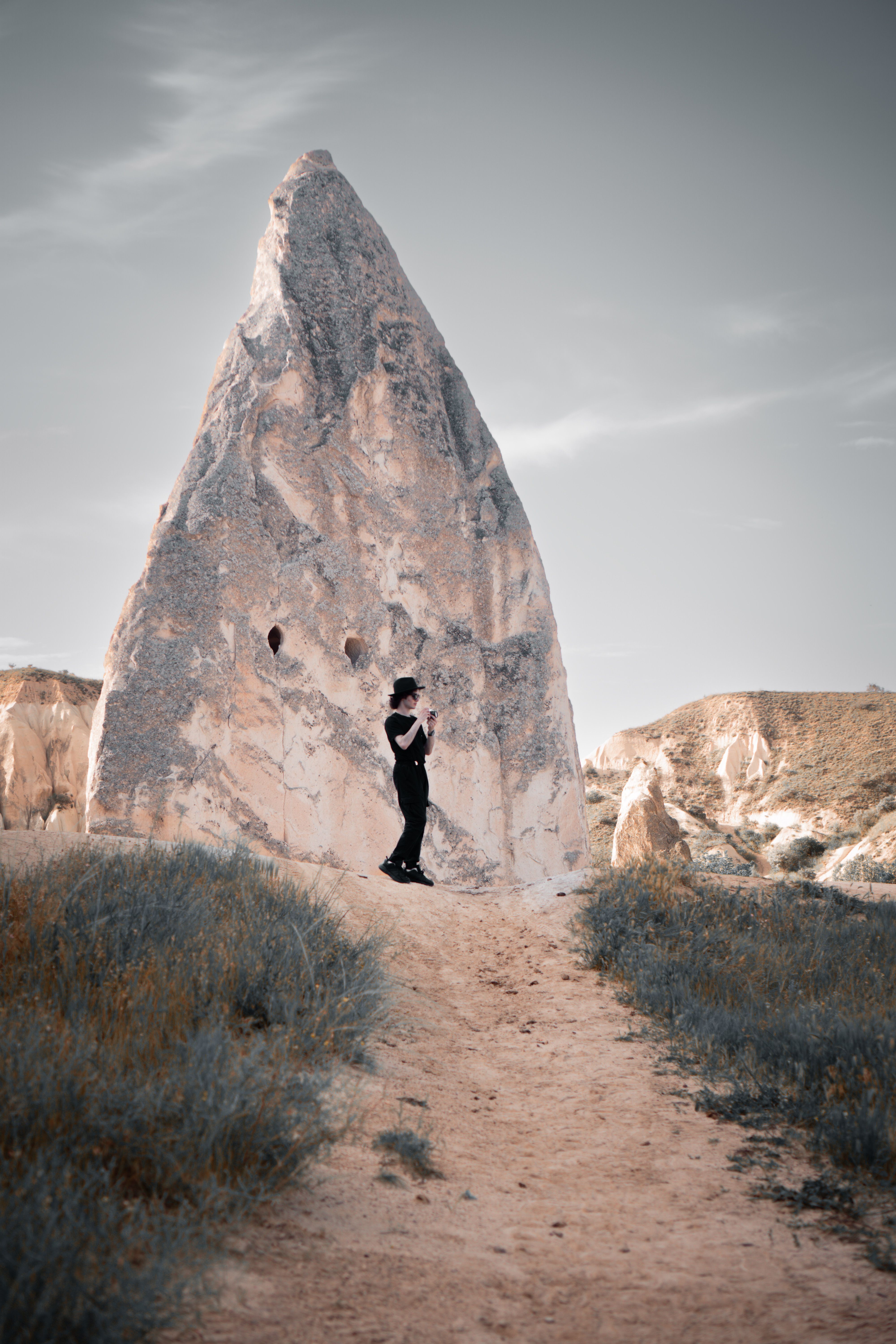 Man Standing in Front of a Stone on a Desert · Free Stock Photo