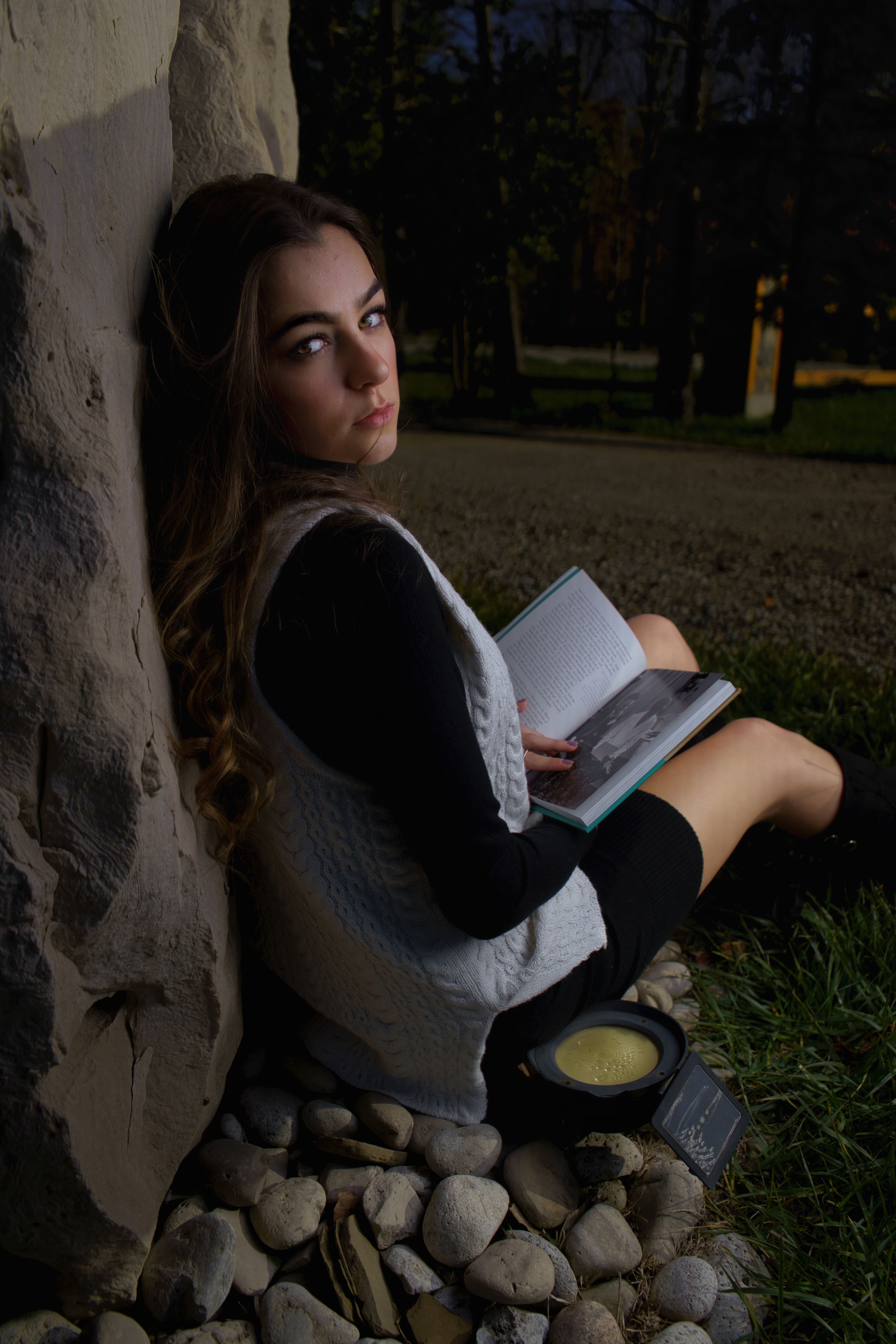 A woman sitting on a rock reading a book · Free Stock Photo