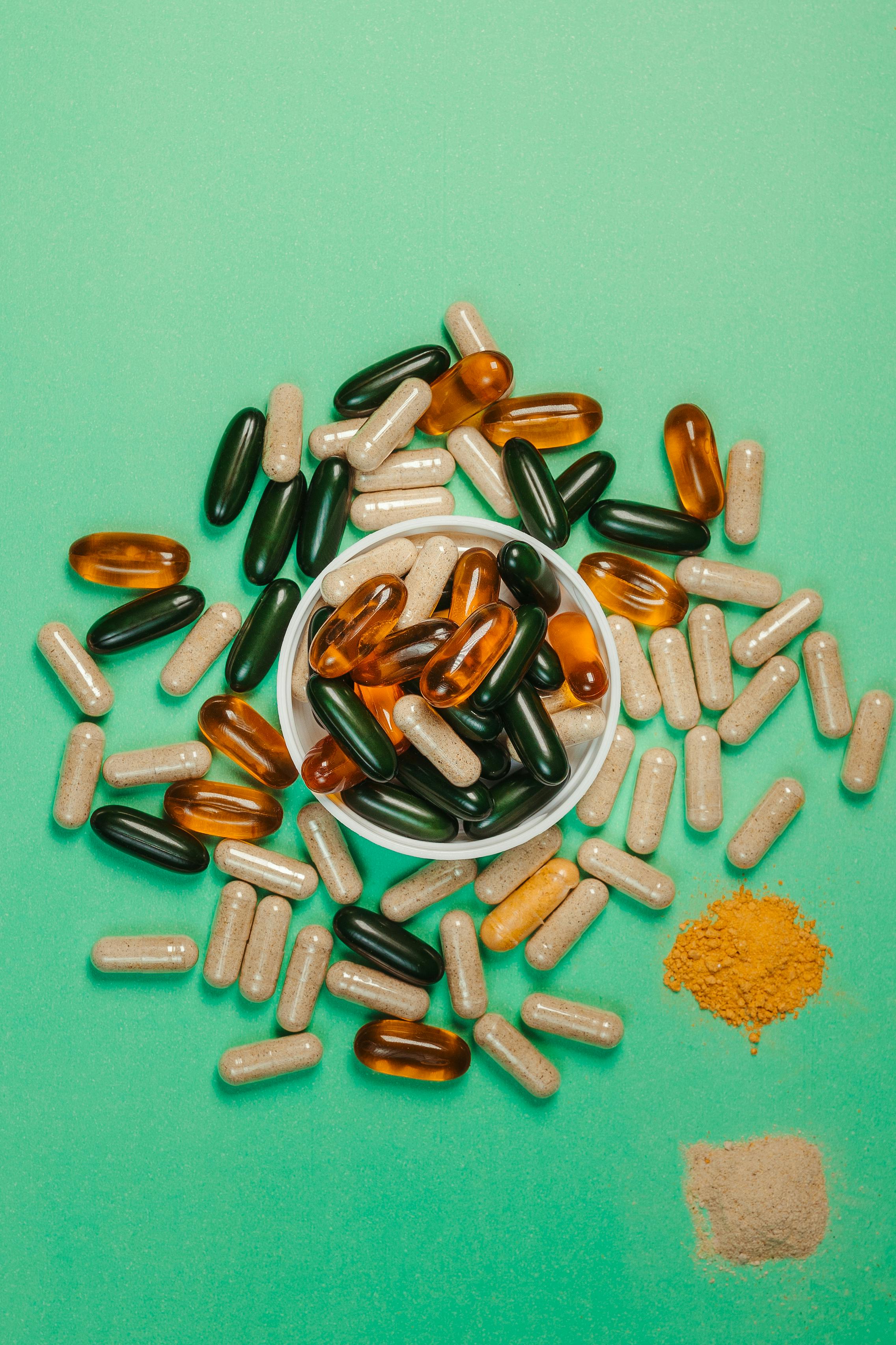 Multi Colored Capsules and Powder on Green Background · Free Stock Photo