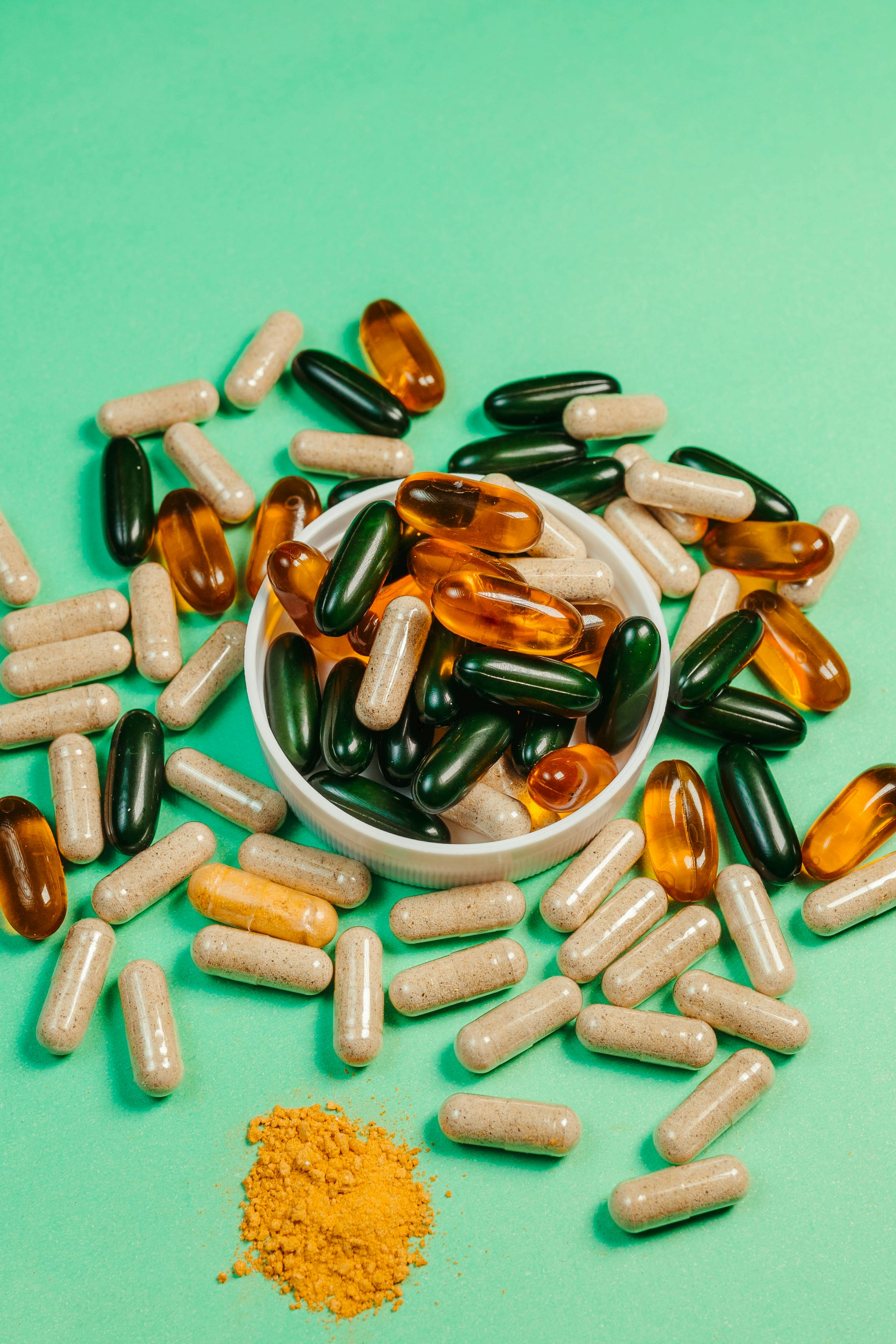 Multi Colored Capsules on Yellow Backgorund and Powder · Free Stock Photo