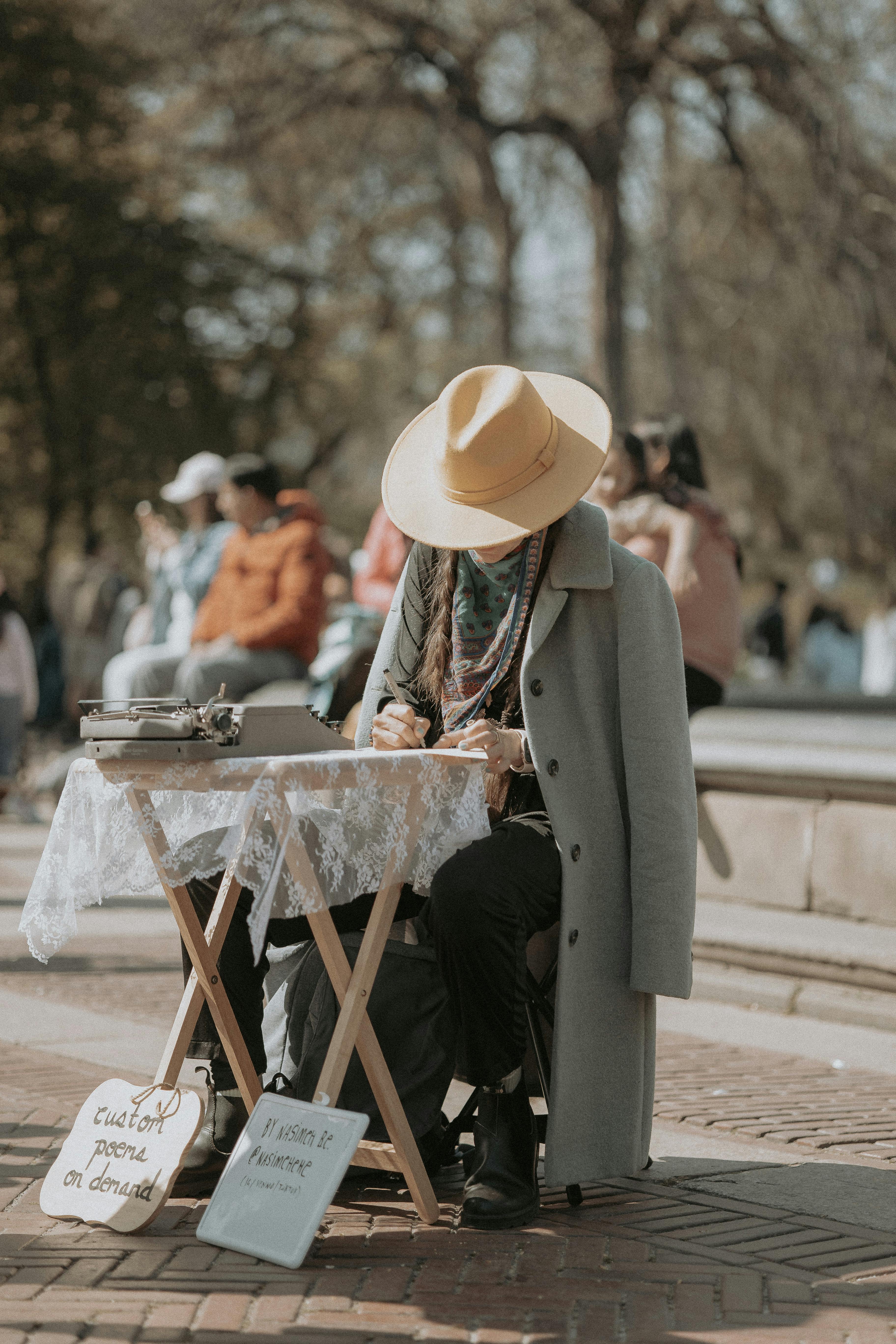 Street Poet in Fedora Hat and Overcoat Sitting at a Table with a ...