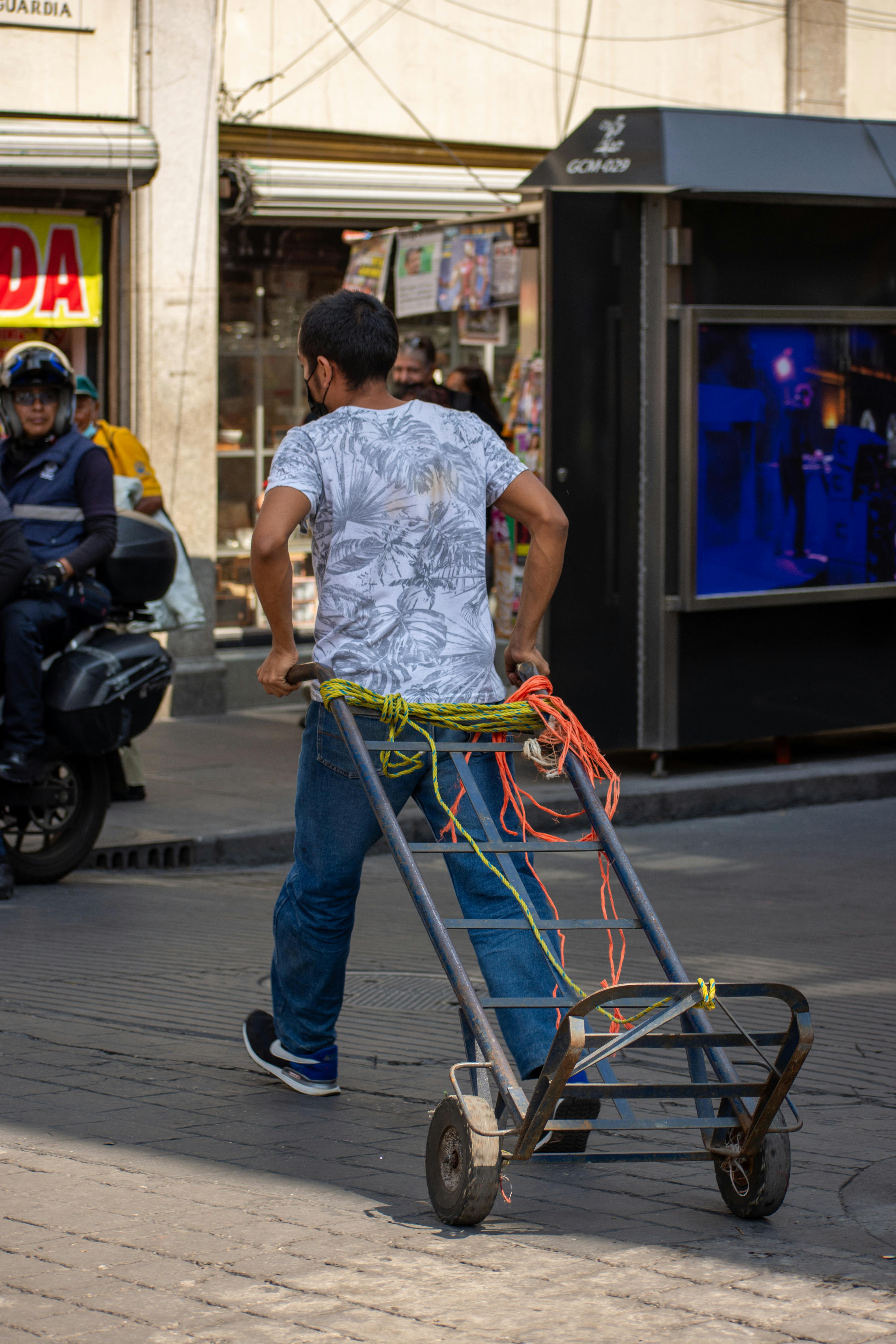 Man Pulling an Empty Trolley on a Street · Free Stock Photo