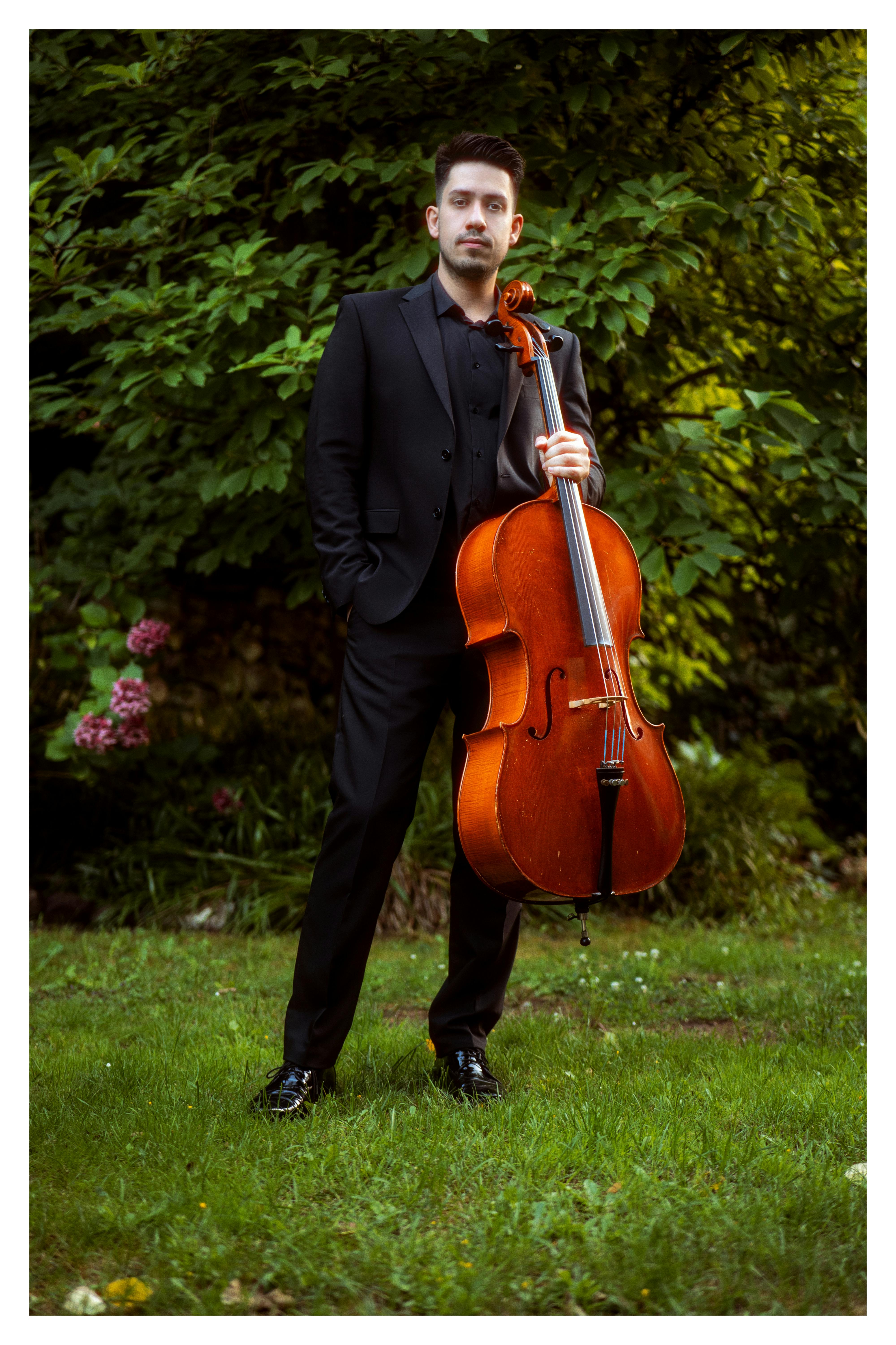 Man Holding Cello in Yard · Free Stock Photo