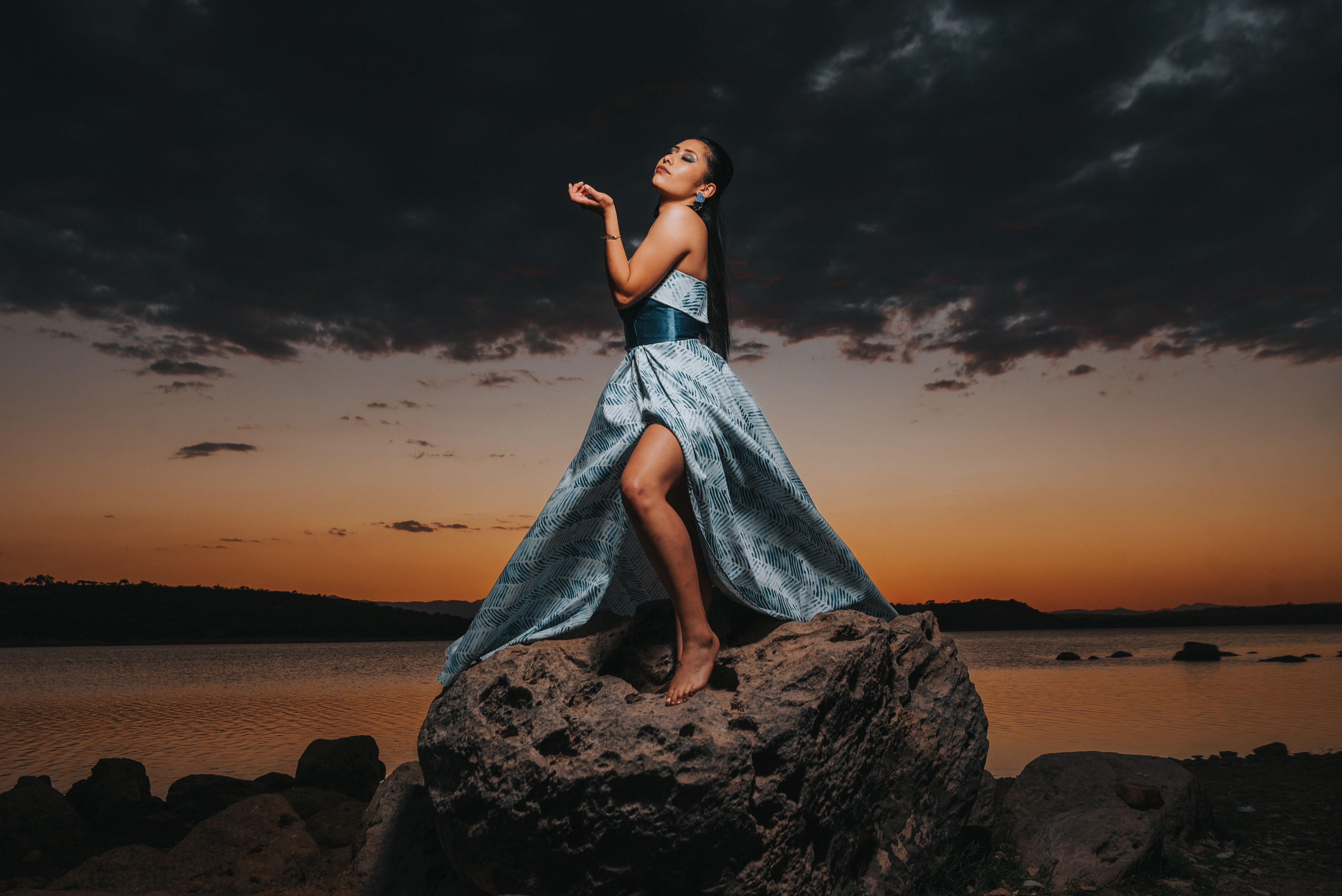 Woman in Long Blue Gown Standing on a Big Stone at a Seashore · Free ...