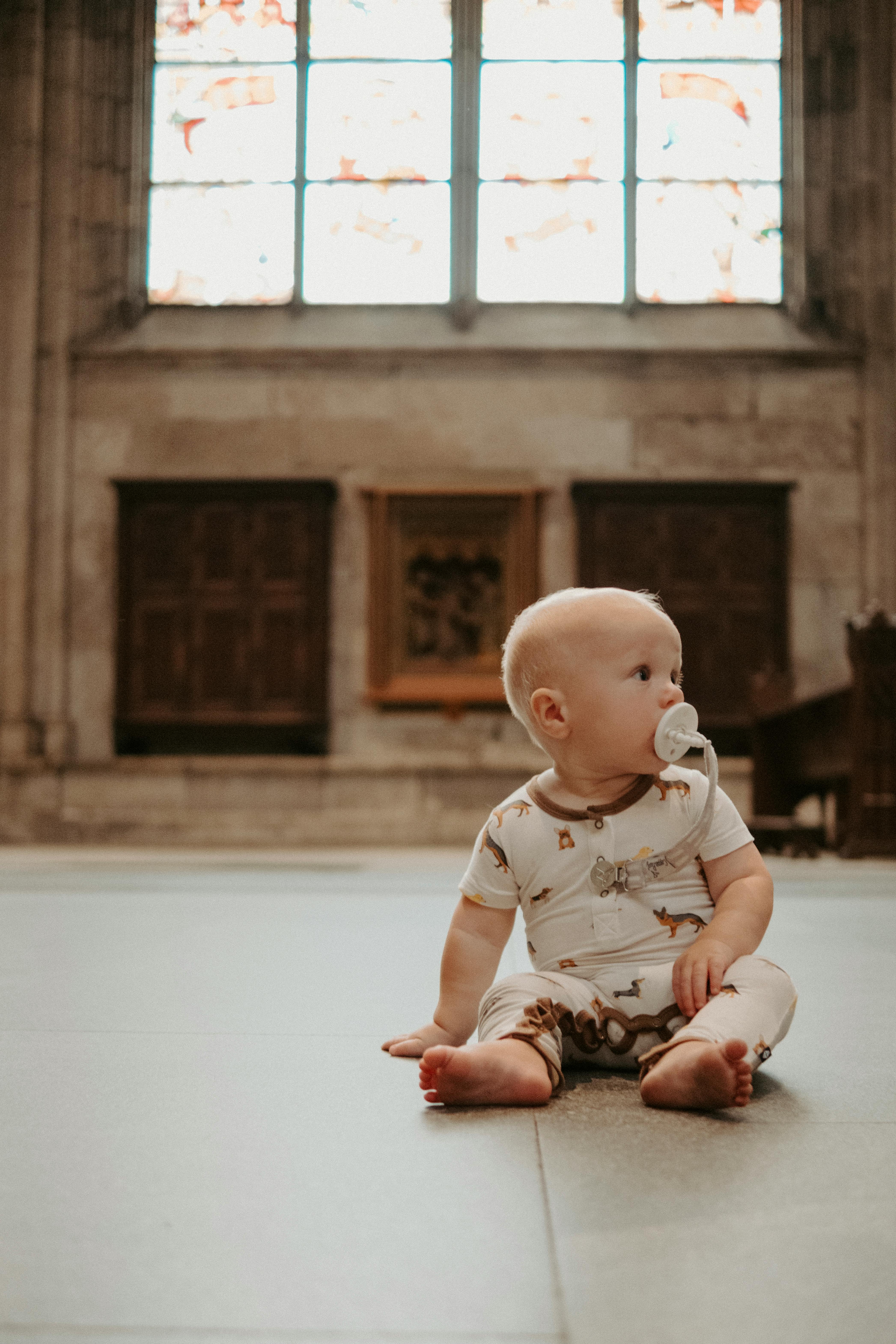 Toddler with a Dummy Sitting on a Floor in a Church · Free Stock Photo