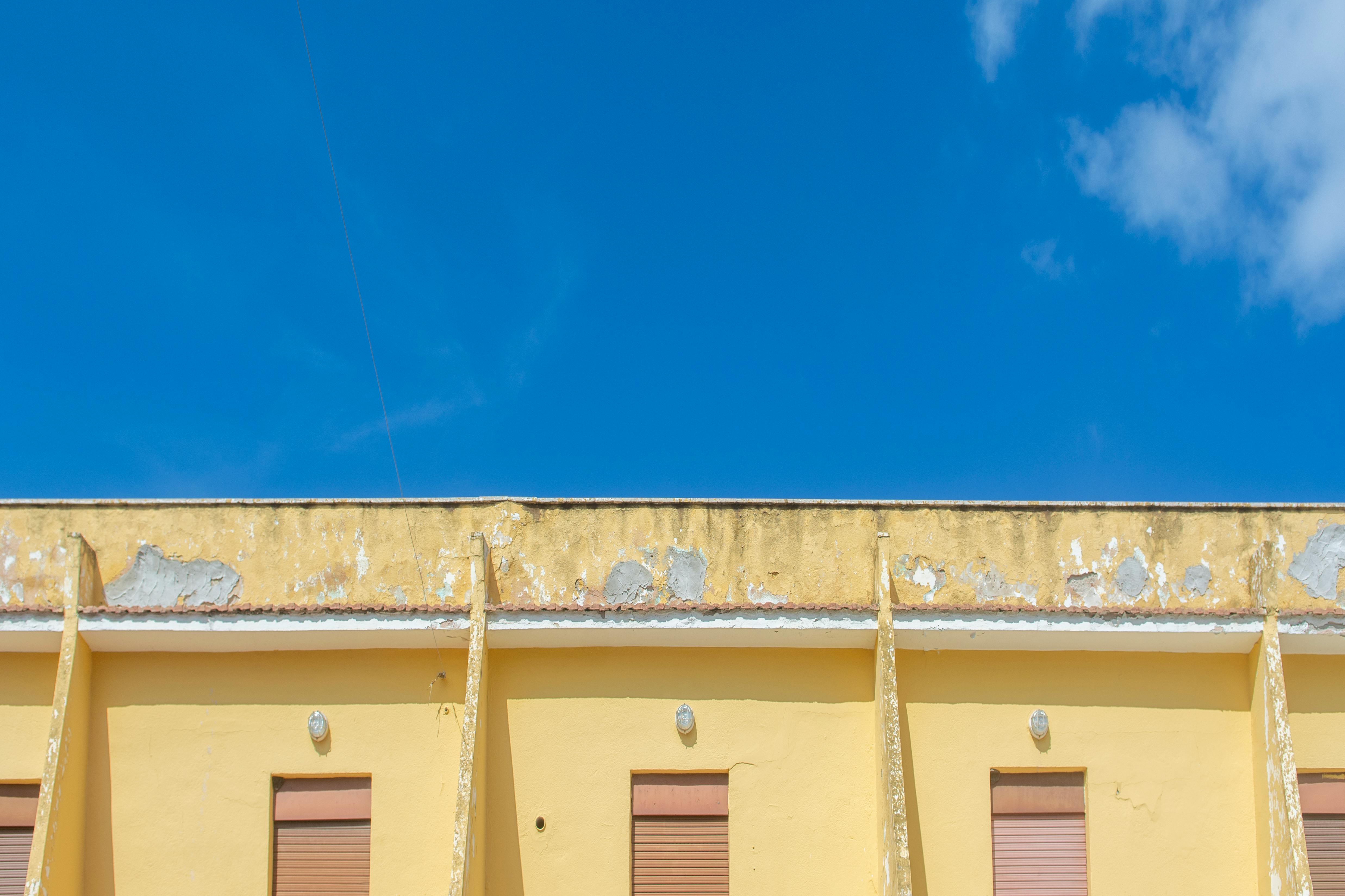 Decay Old Yellow Building Facade on Blue Sky · Free Stock Photo