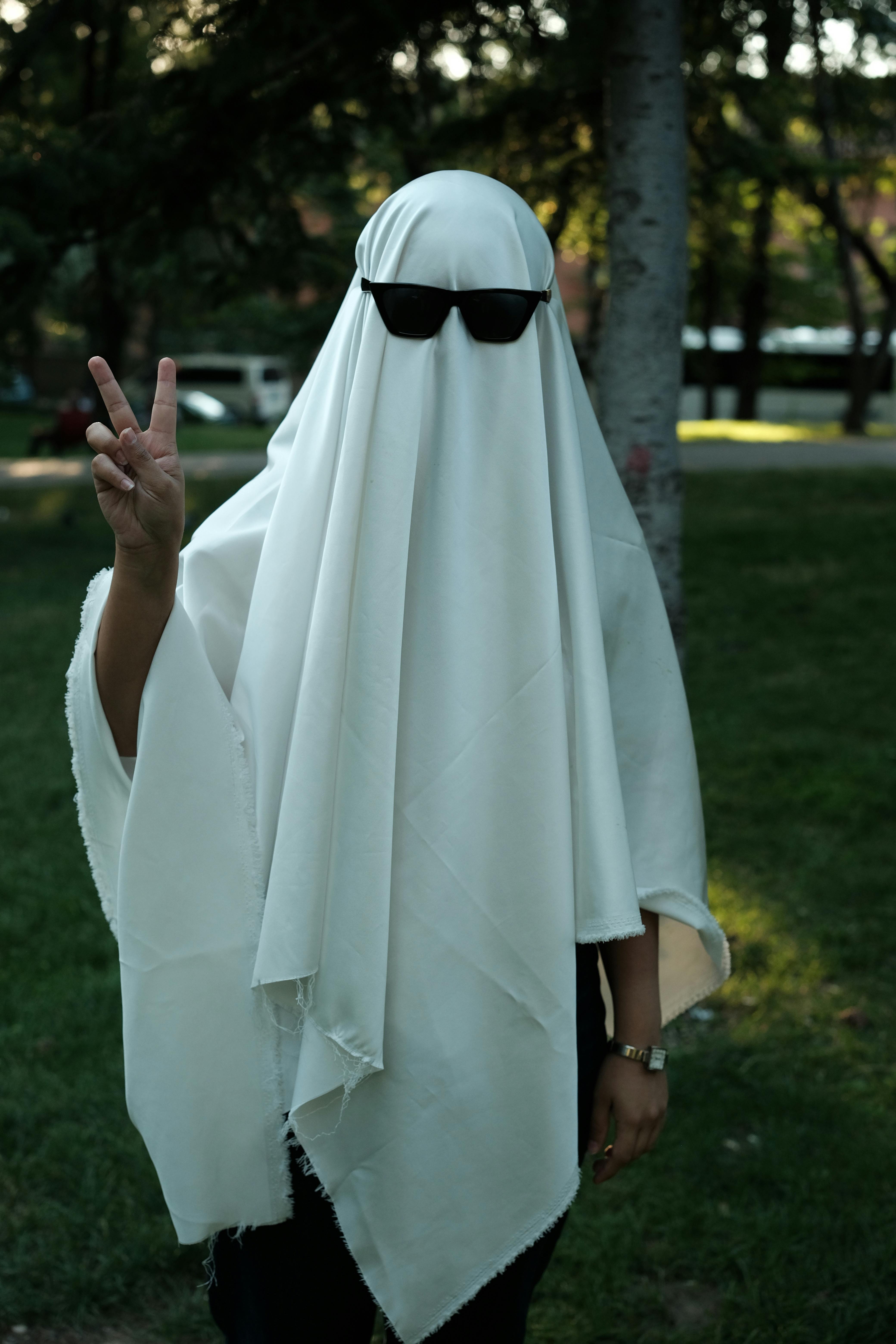 A Person Dressed as a Ghost Wearing a White Sheet and Sunglasses · Free ...