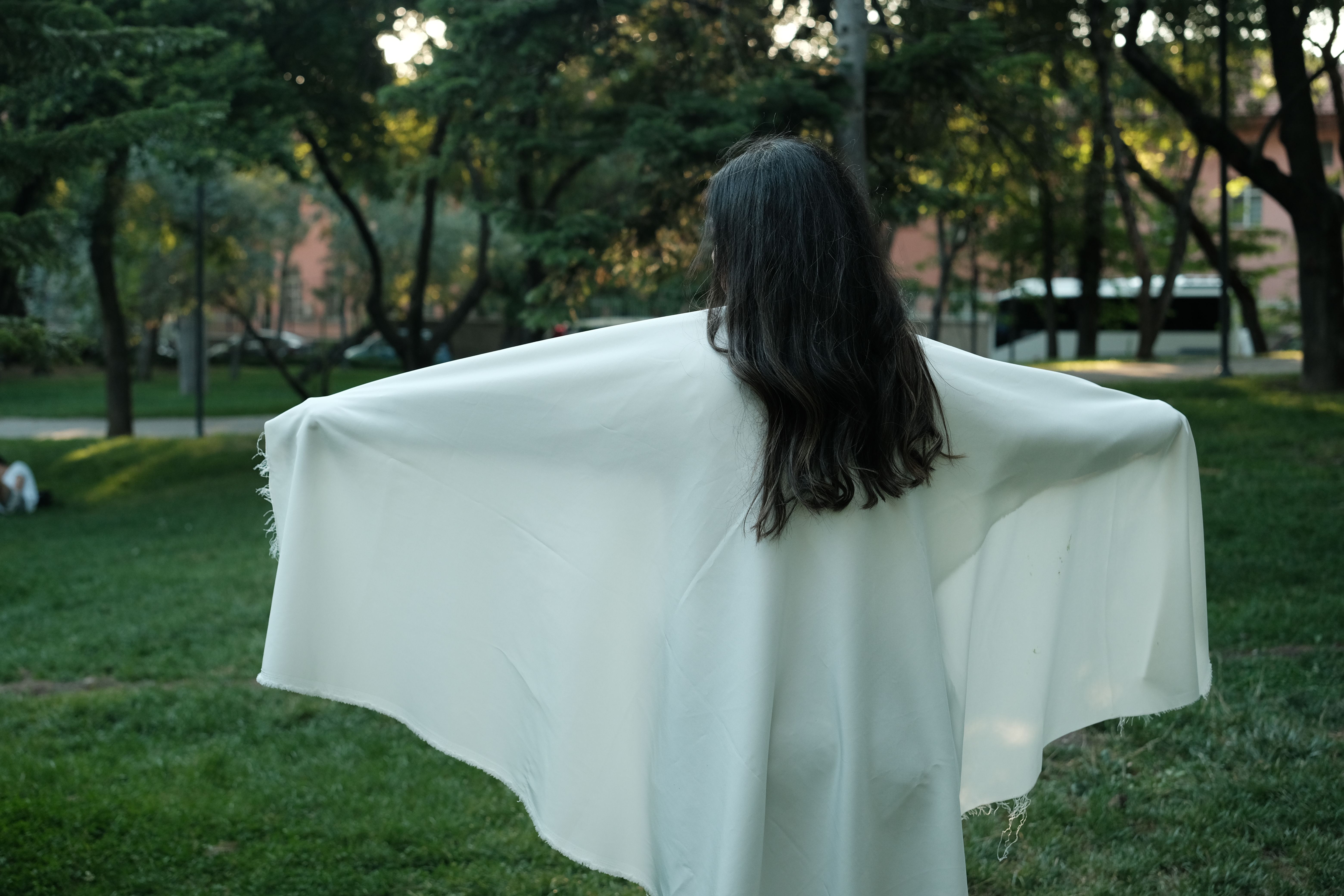 Back View of a Woman Wearing a White Sheet and Standing with Arms ...