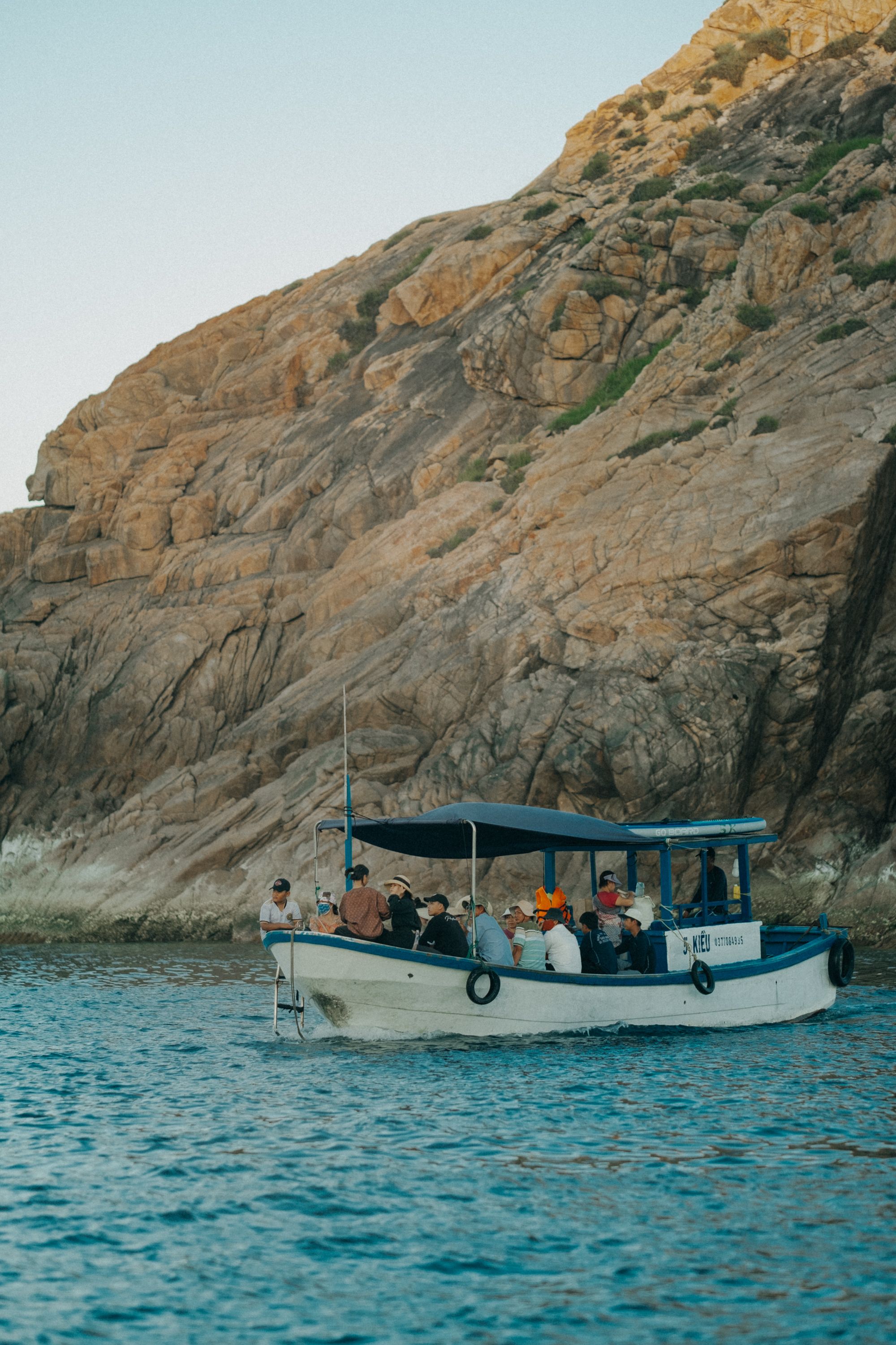 A Boat with Tourists Sailing near a Cliff · Free Stock Photo