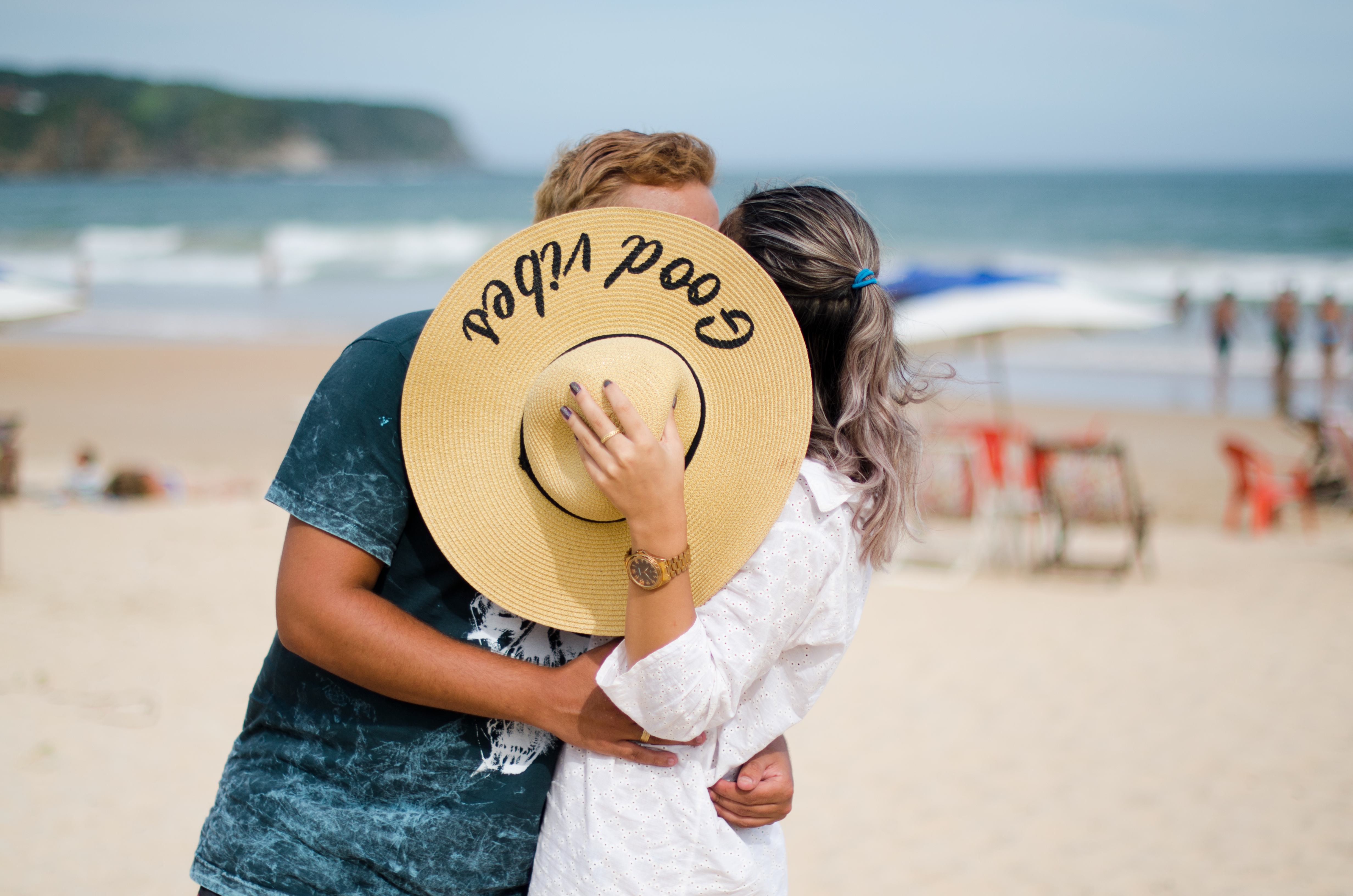 Couple Kissing behind Hat on Beach · Free Stock Photo