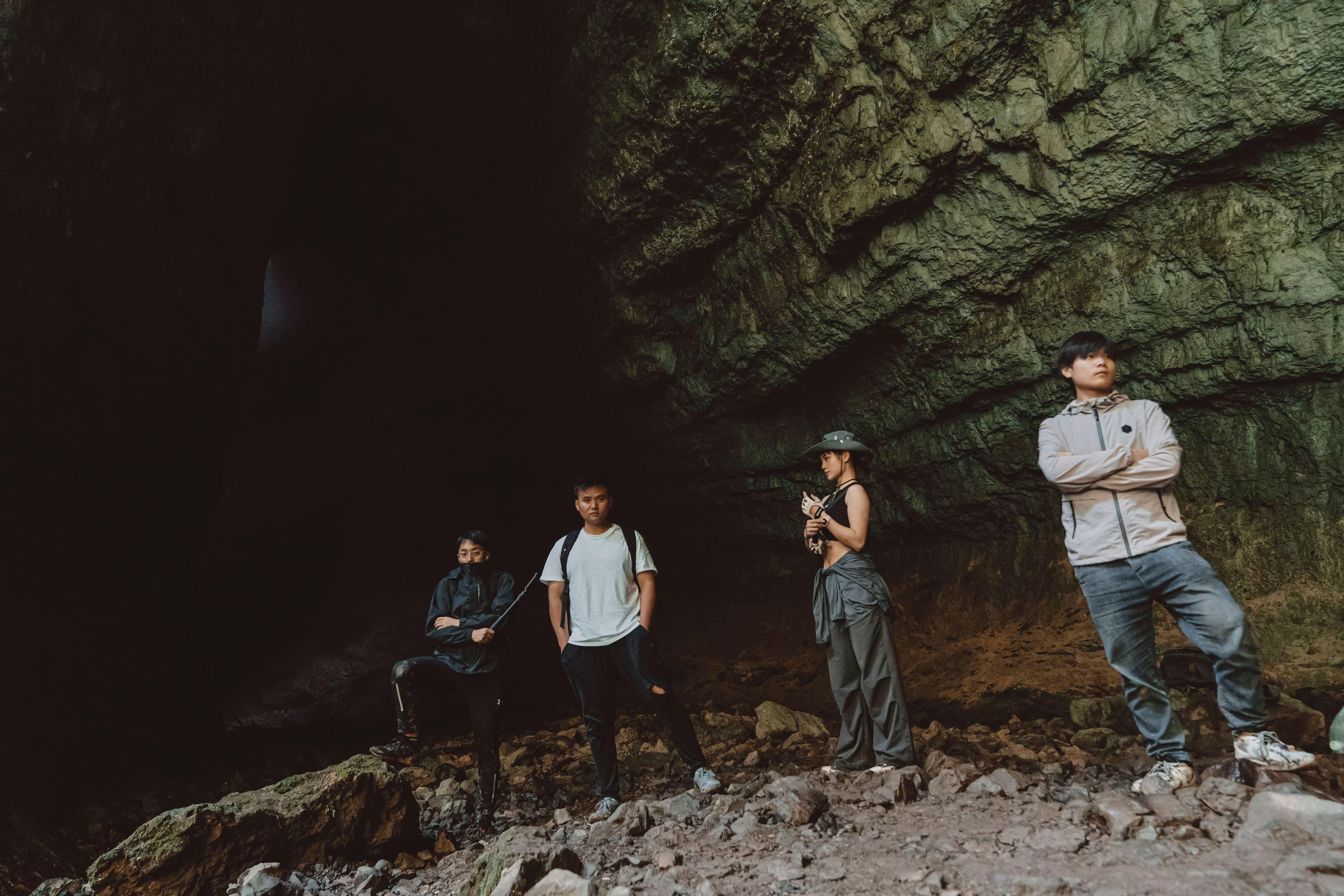 Woman and Men Standing near Cave Rocks · Free Stock Photo
