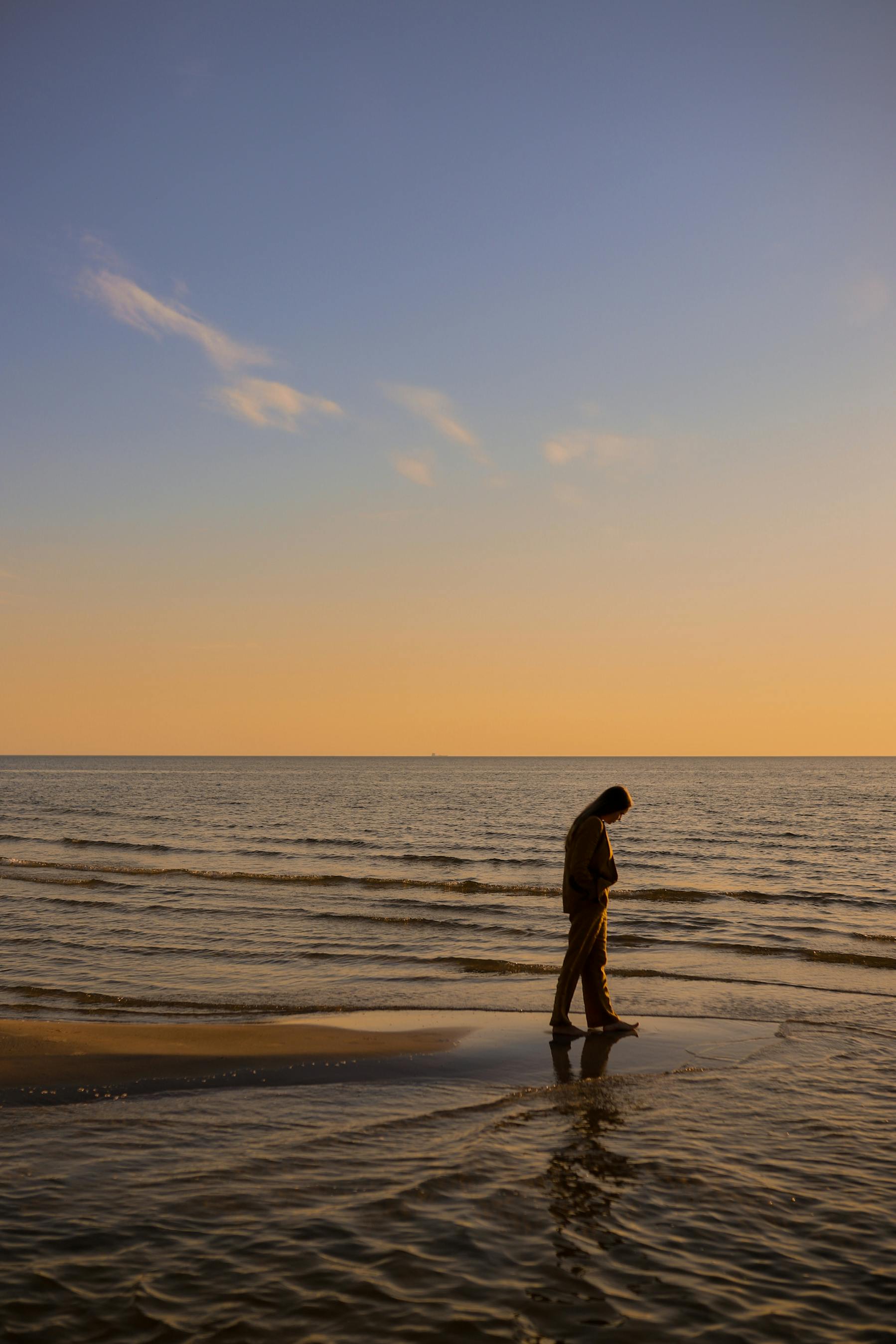 Person Standing and Looking Down on Sea Shore at Sunset · Free Stock Photo