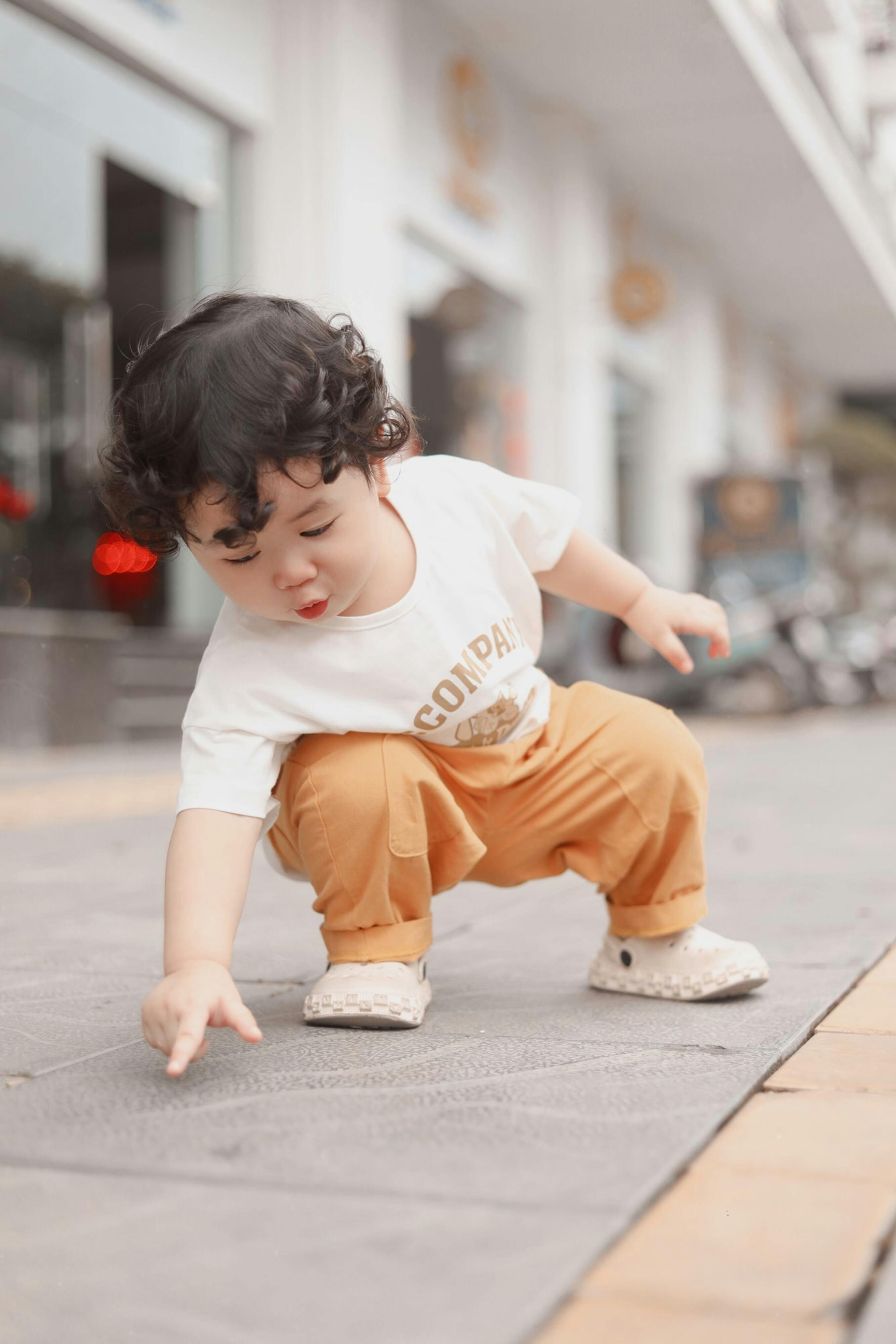 A Cute Baby Crouching on a Pavement · Free Stock Photo