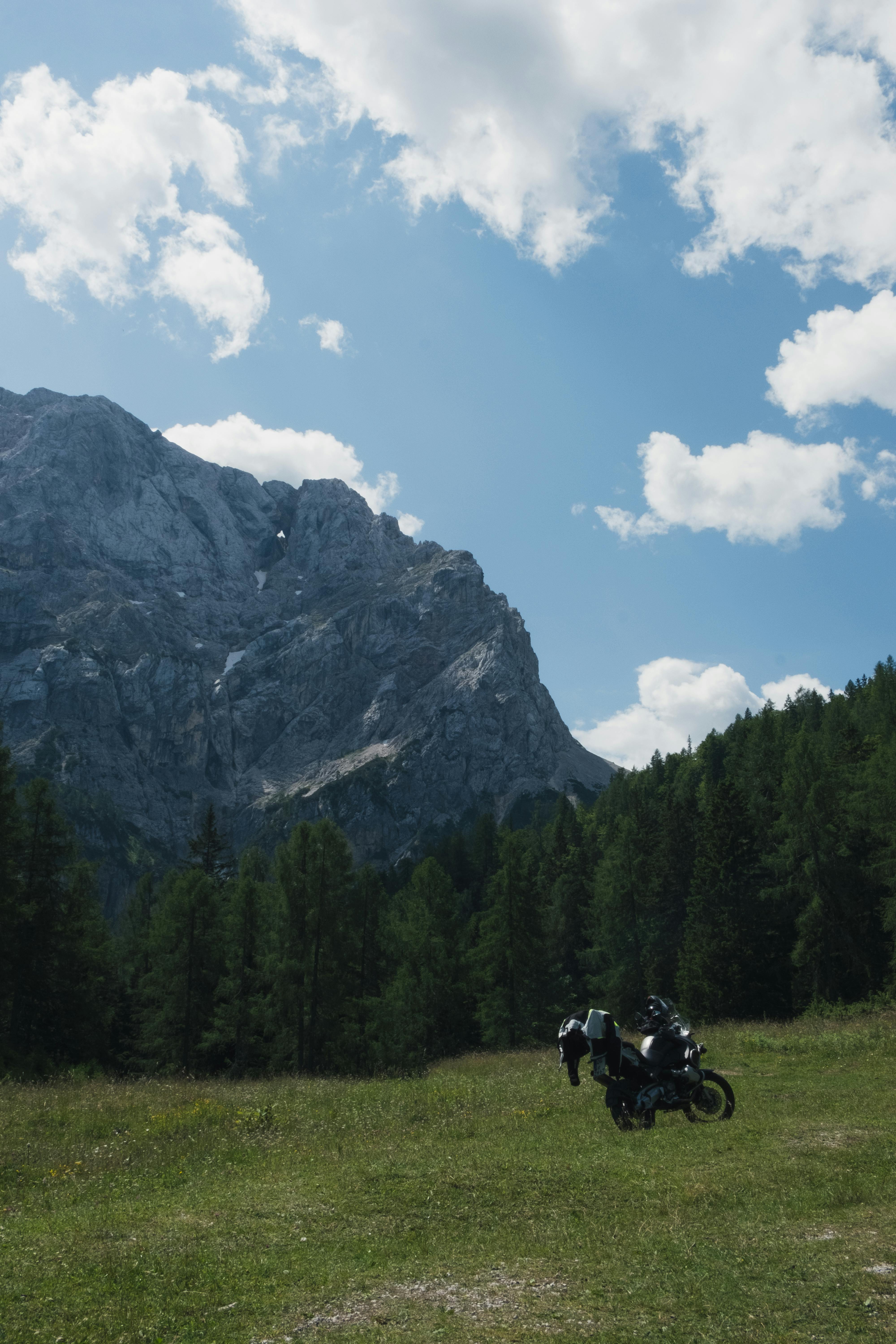 Motorbike on Grassland with Forest and Mountain behind · Free Stock Photo