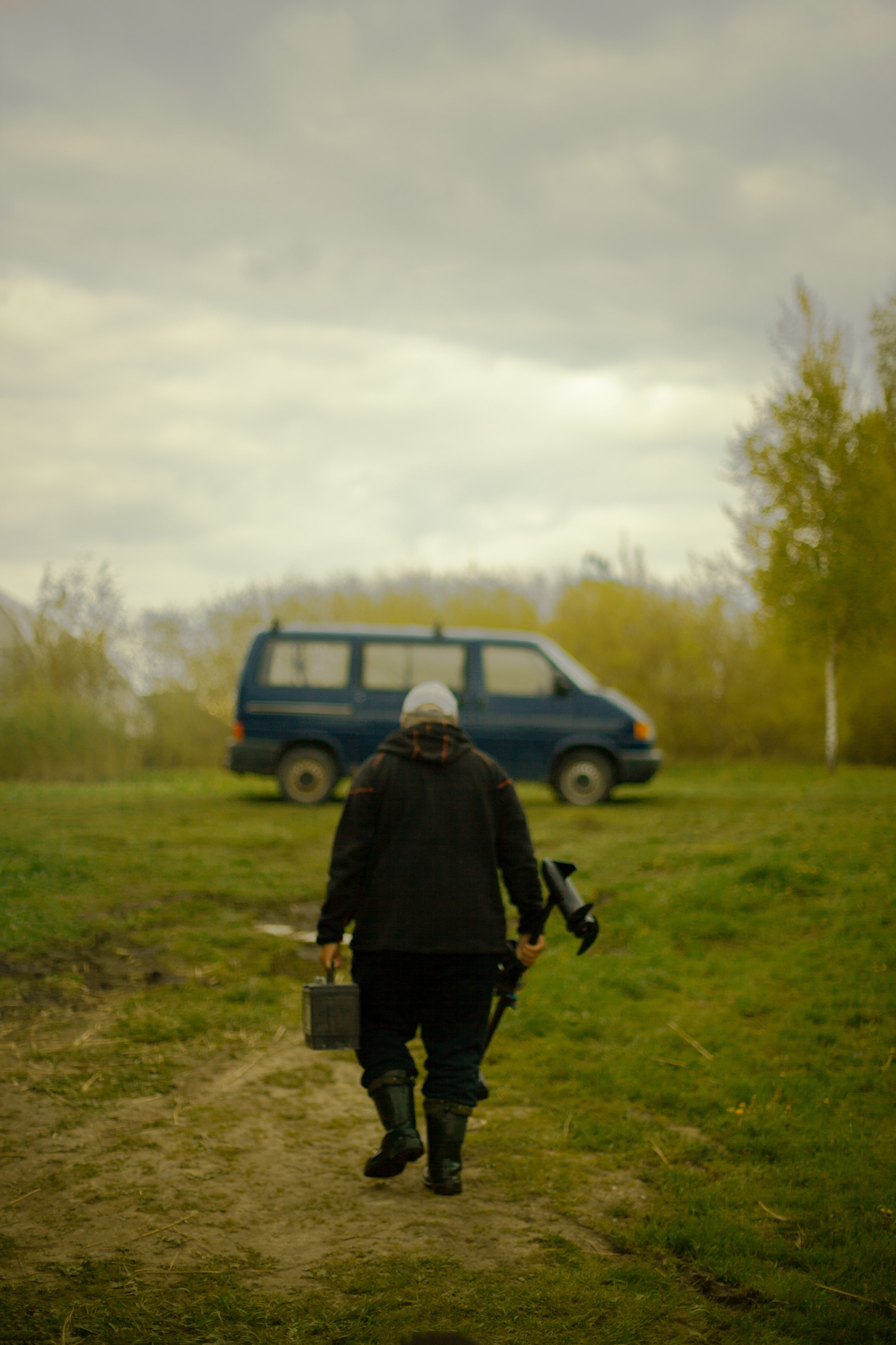 Man in Rubber Boots Walking to Van Carrying Car Battery and a Tool ...