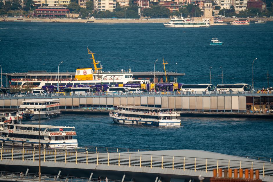 A bustling scene of Istanbul's harbor, featuring ferries and buses in motion.