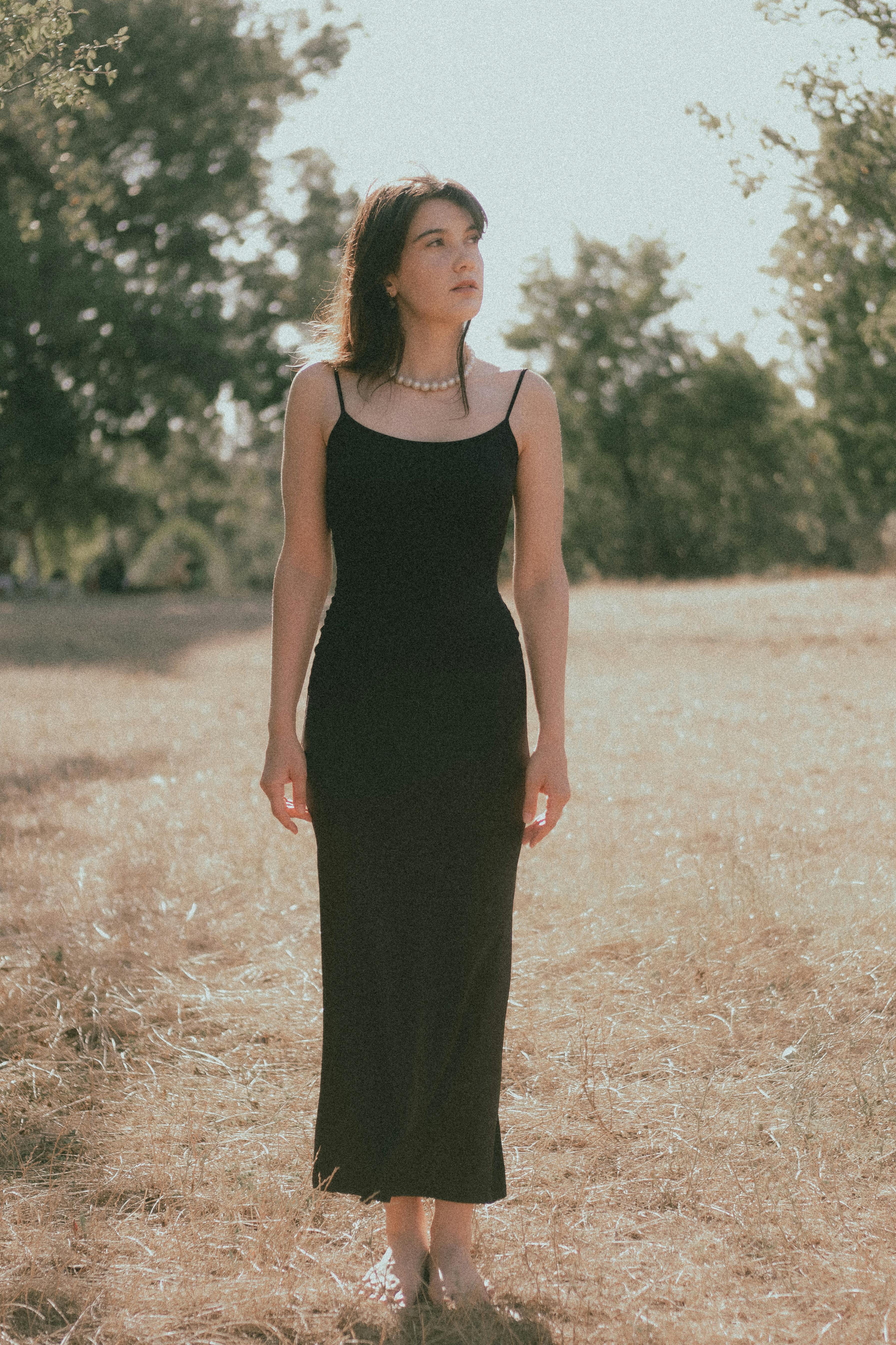 Woman in Black Bodycone Dress with Spaghetti Straps Standing on Grass ...