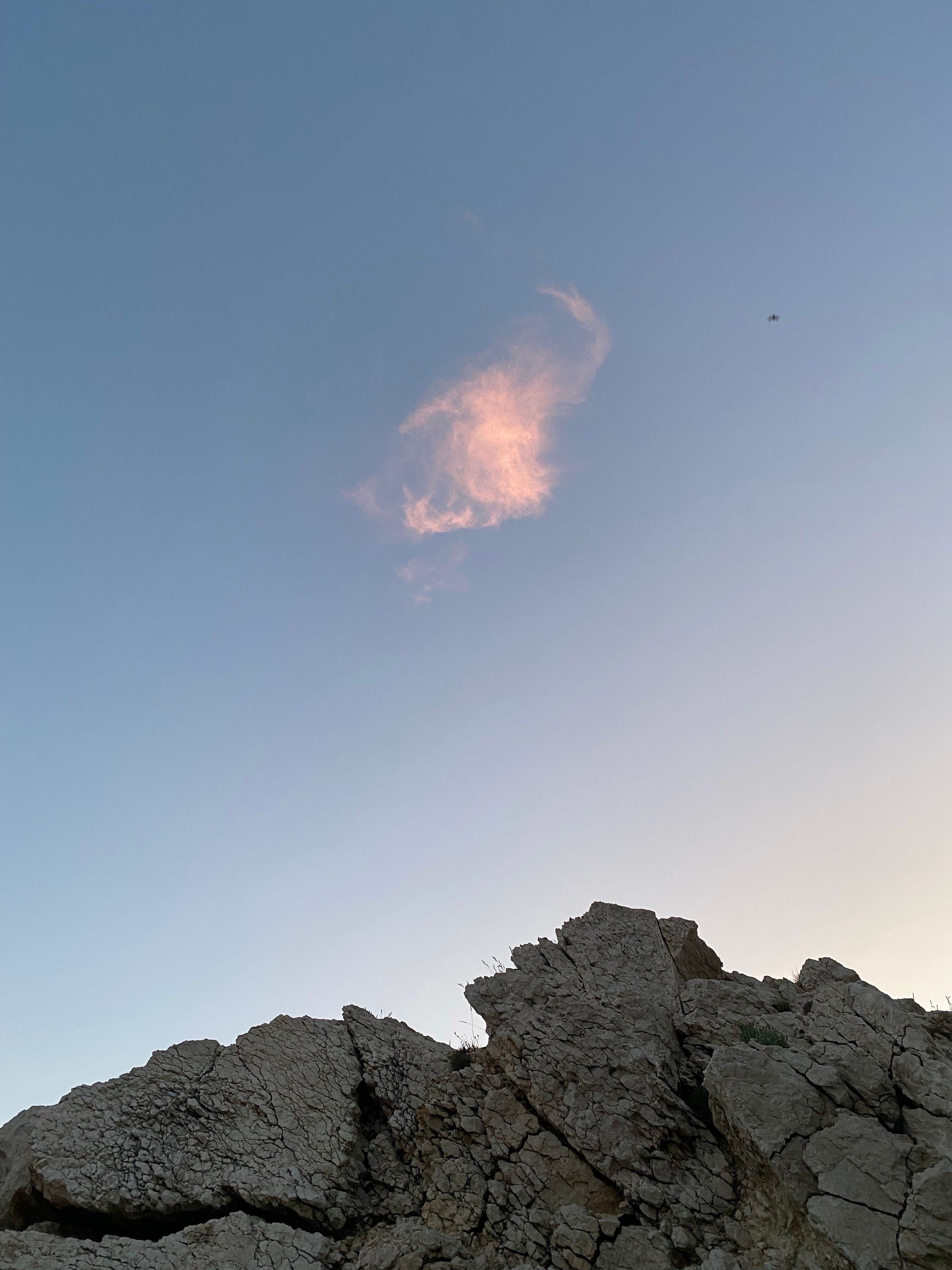 Little Pink Cloud in a Blue Sky over Gray Rocks · Free Stock Photo
