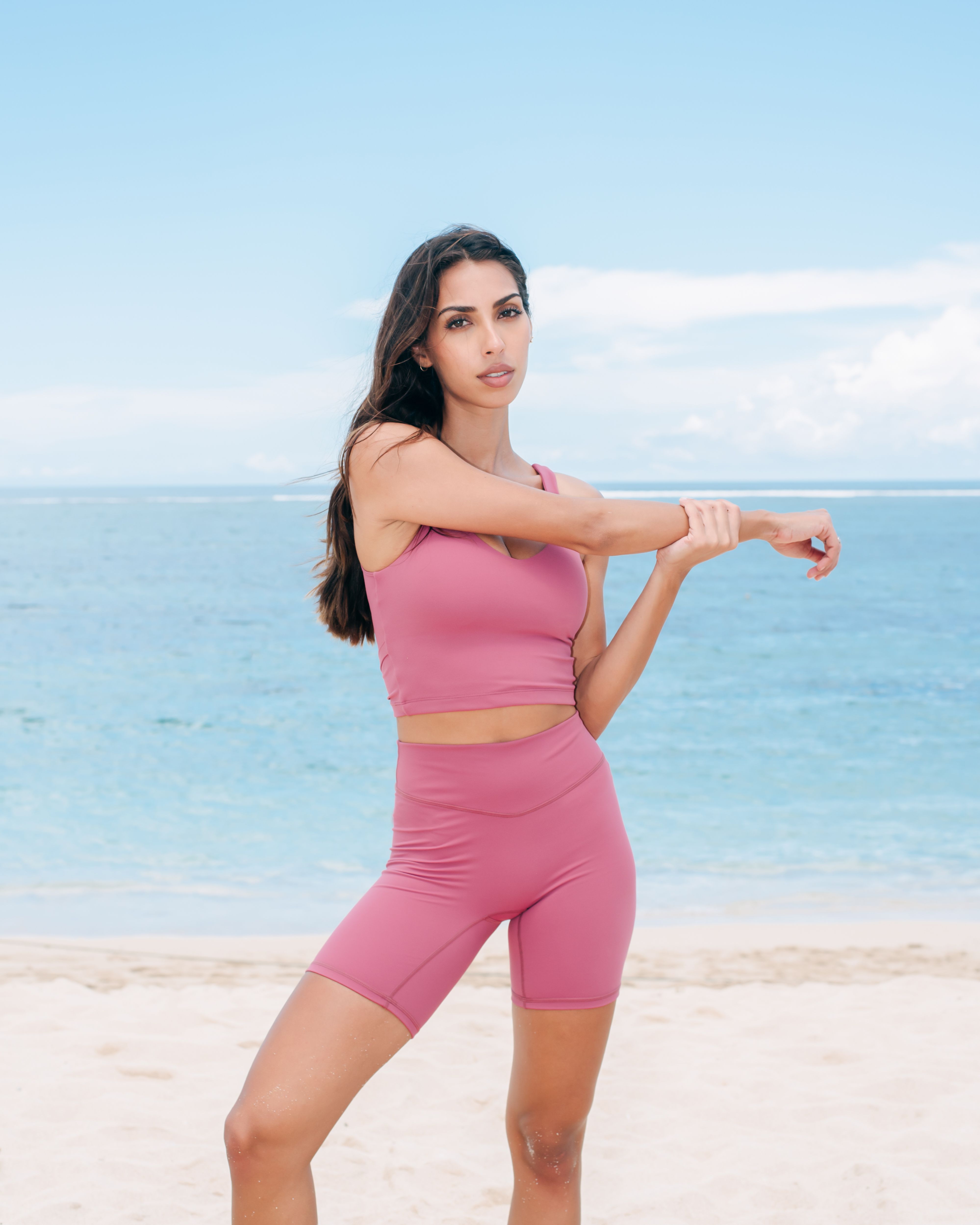 Model in a Pink Sportswear Stretching at the Beach · Free Stock Photo
