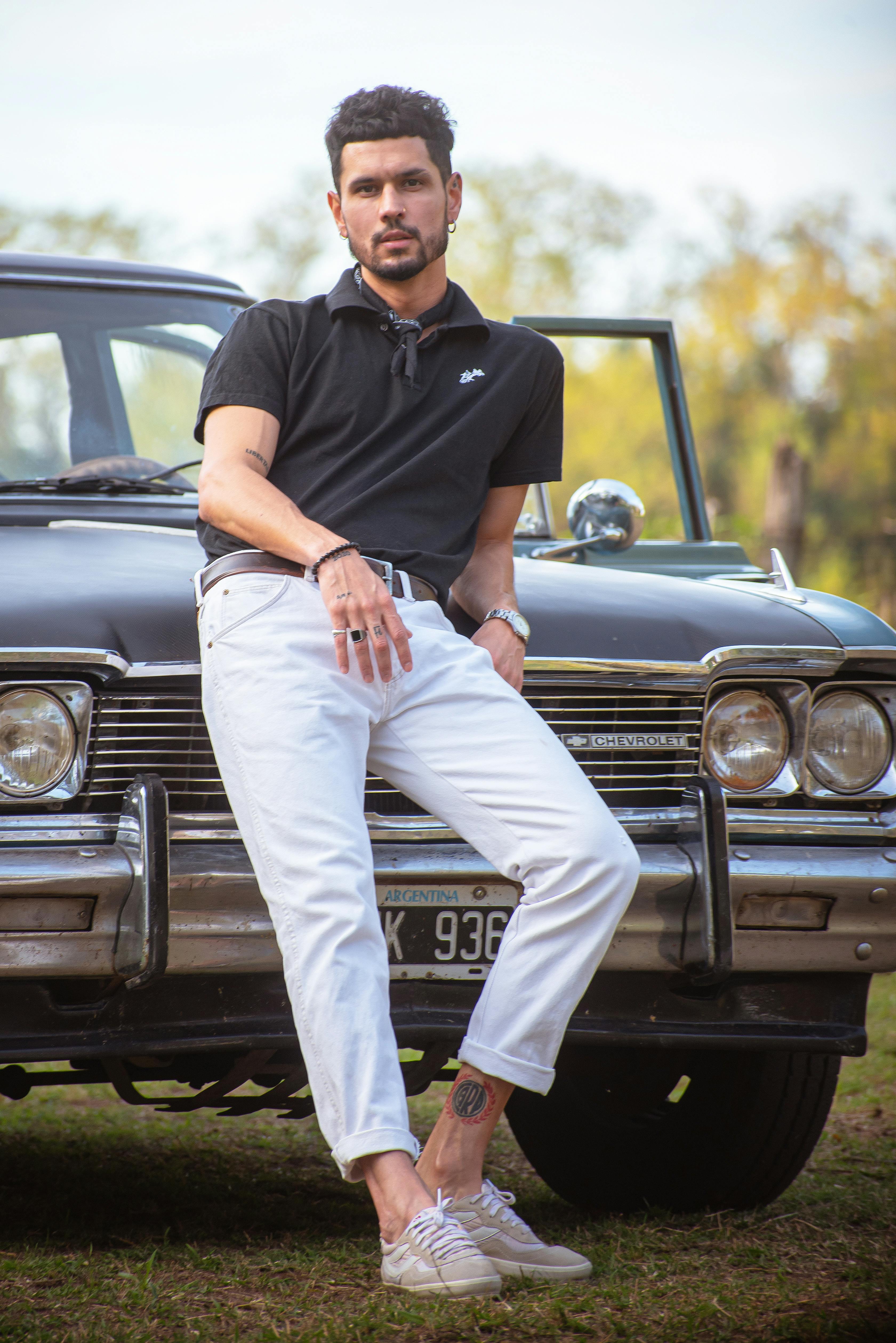 Model in a Black Polo Shirt and White Pants Leaning on a Classic ...