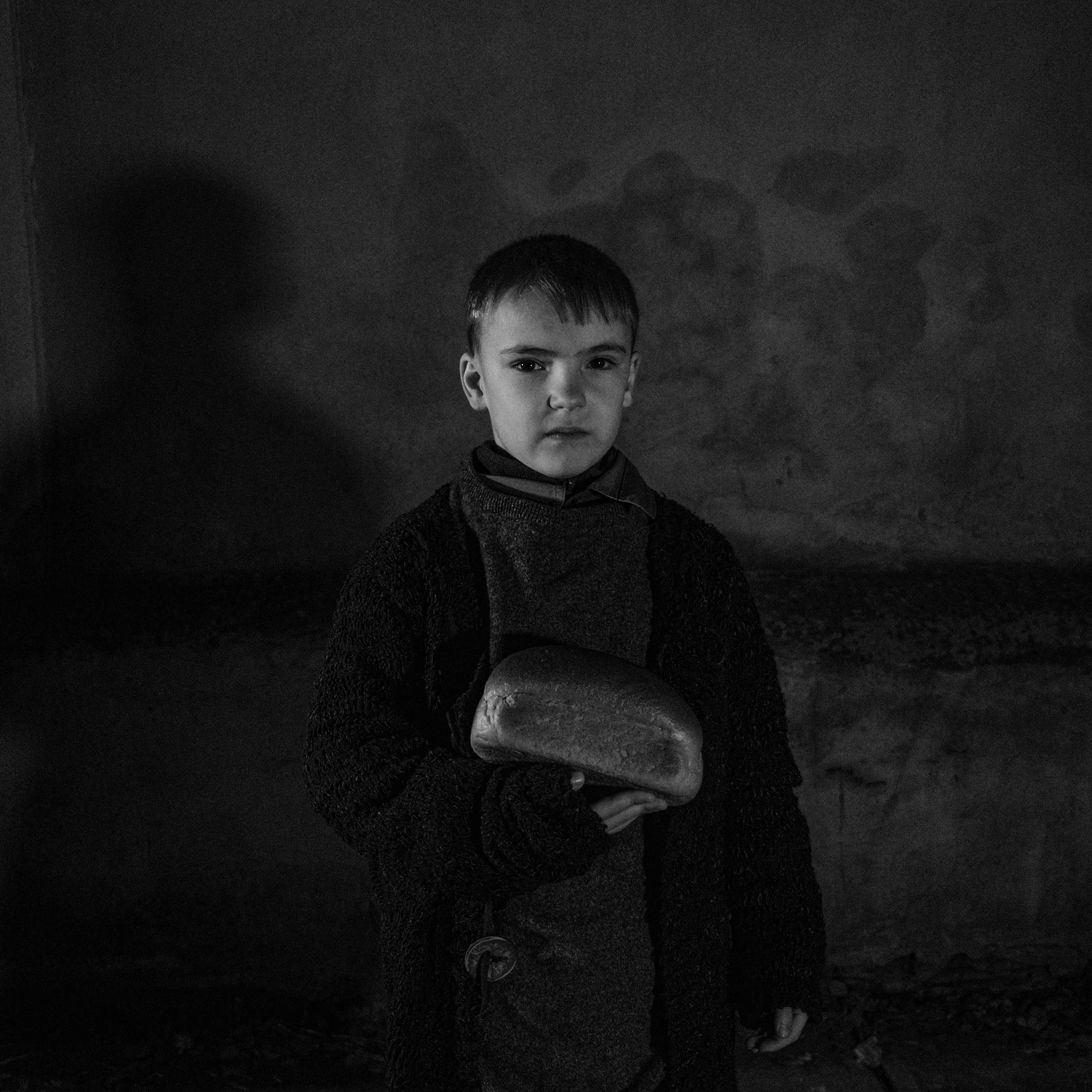 Black and White Portrait of a Boy Holding a Bread Loaf · Free Stock Photo