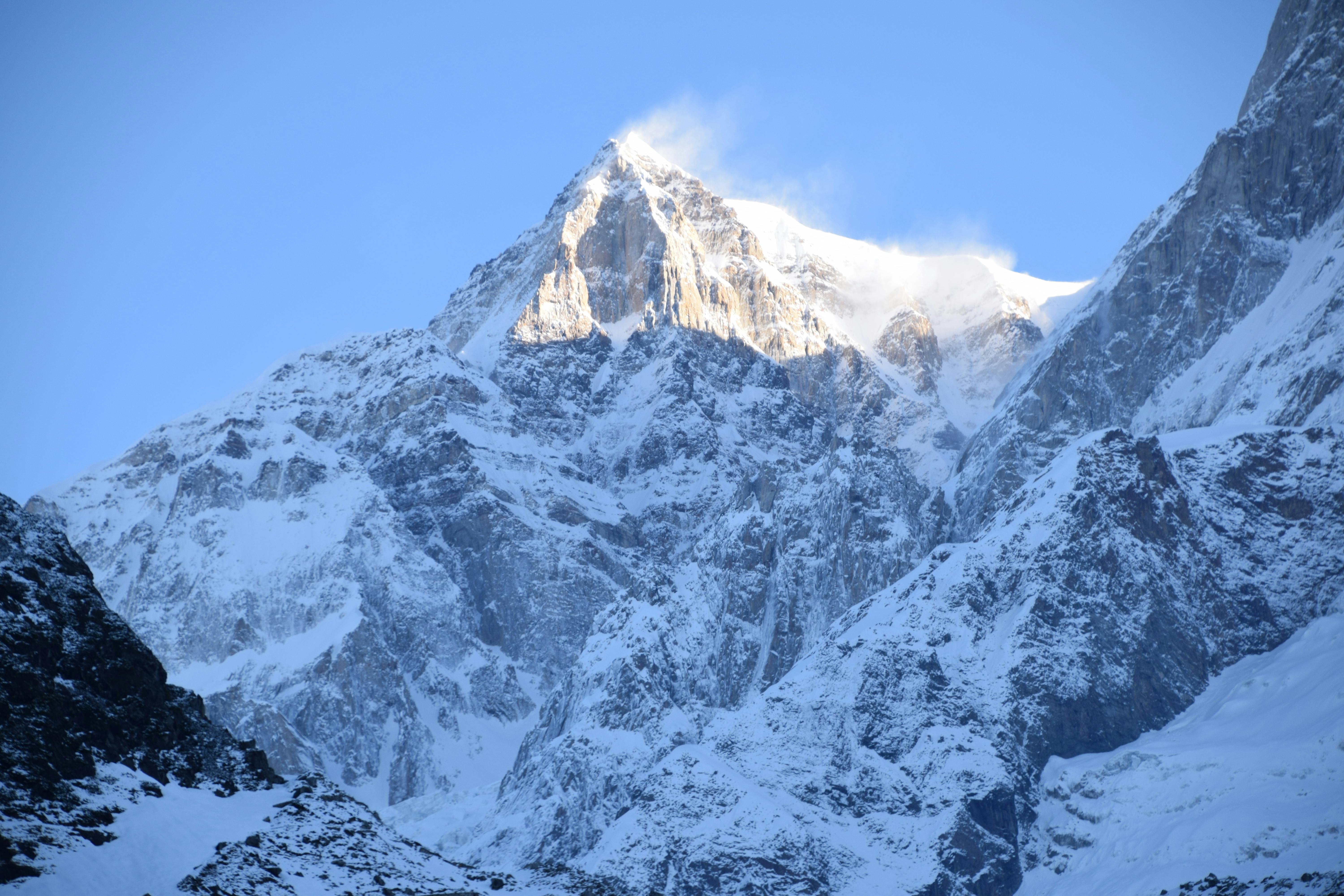 Wind Blowing Snow from a Sunlit Mountain Summit · Free Stock Photo